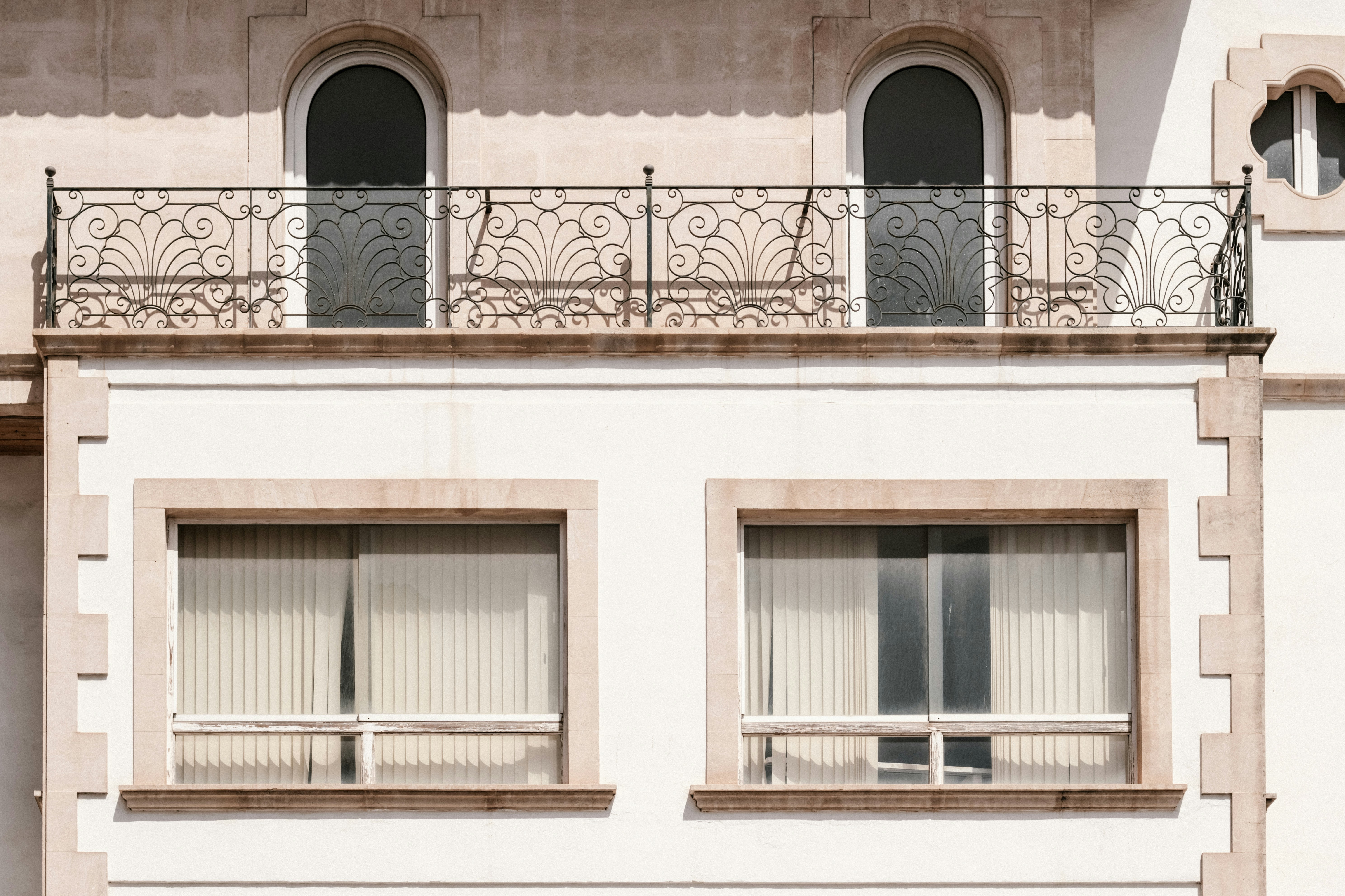 Veranda Veil: Arching Balcony over a Sunlit Facade
