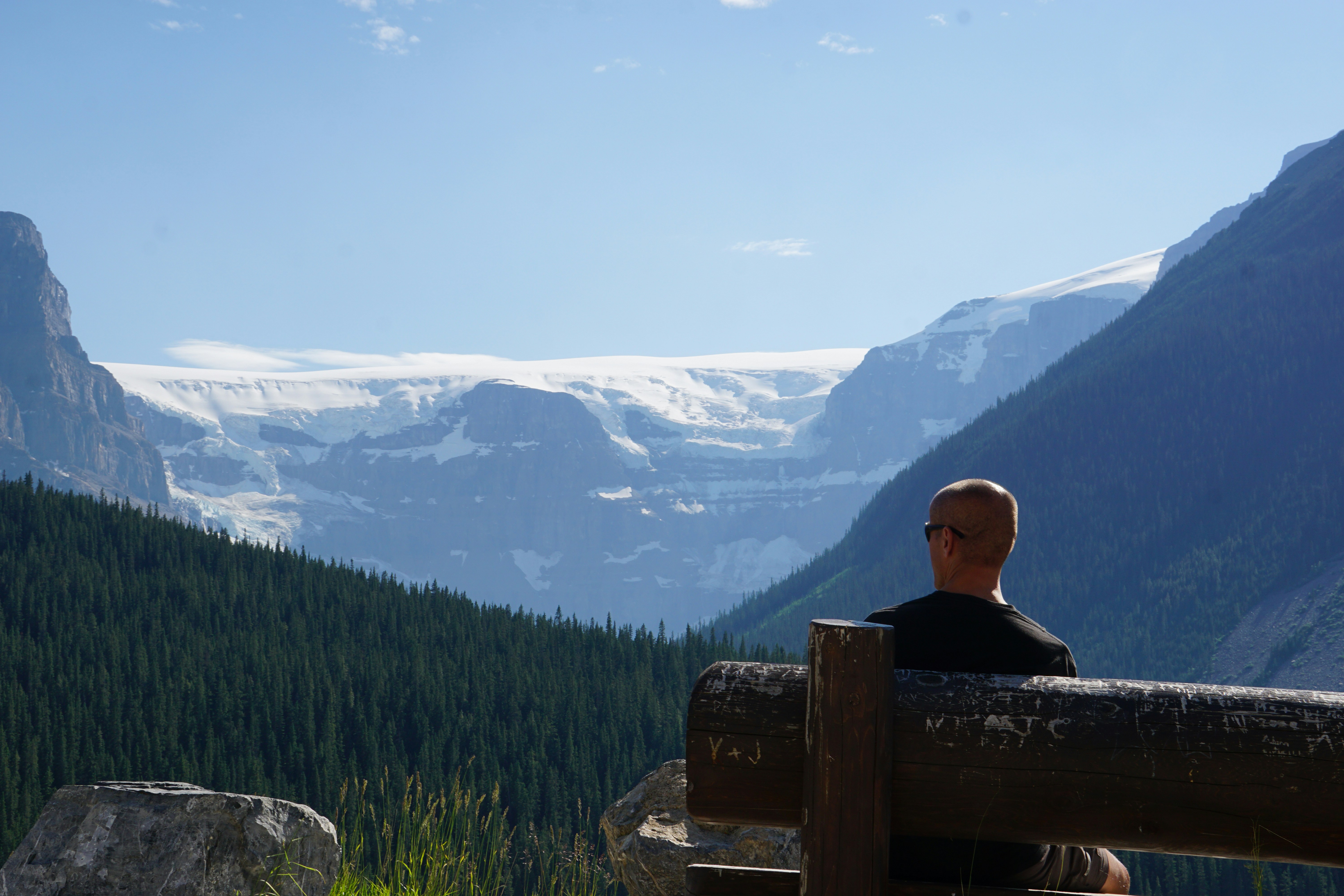 Sunlit overlook: a lone observer amid a glaciered valley