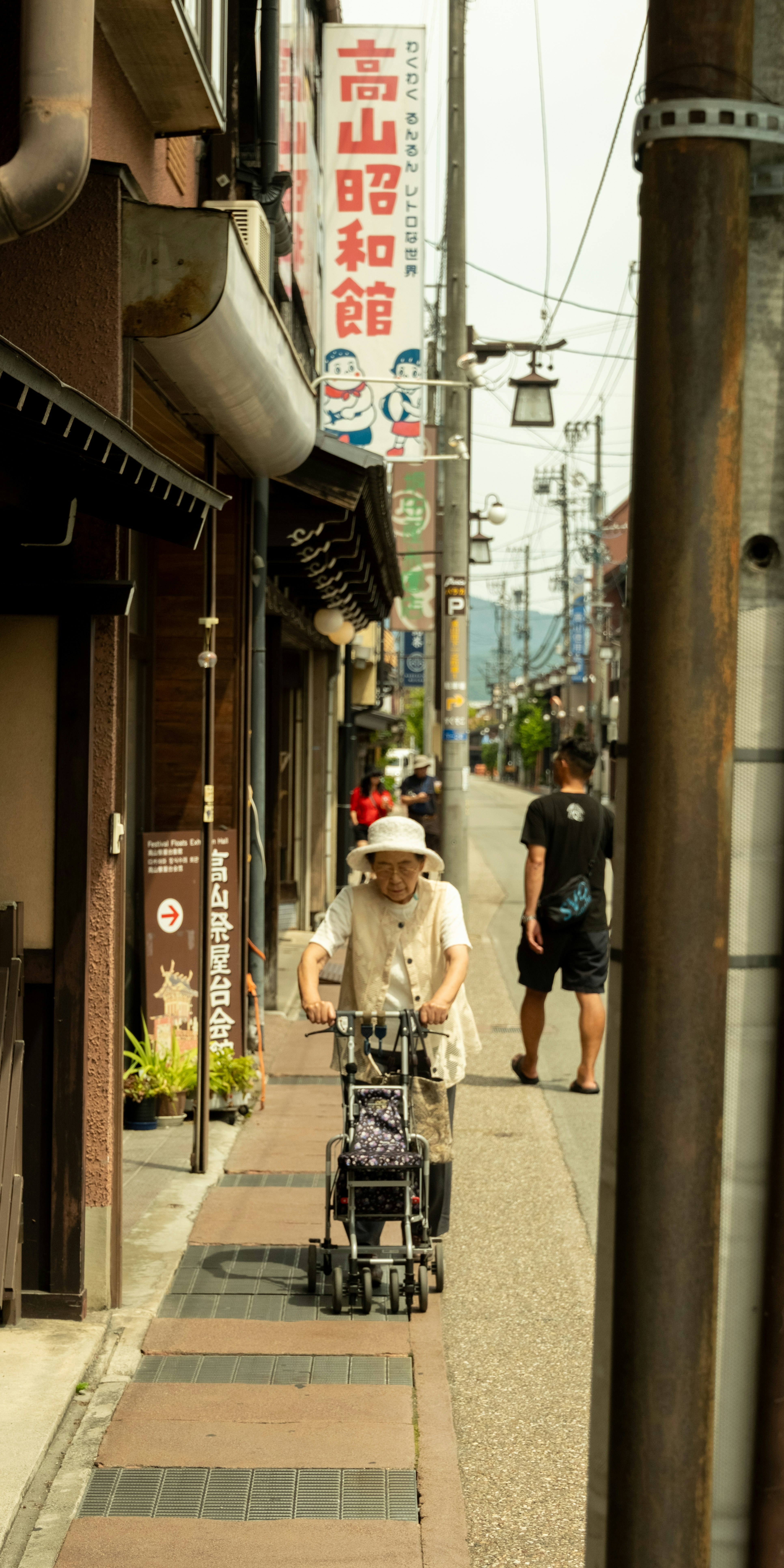 Lined Street Chronicle: A Elderly Pedestrian Steers a Walking Rollator Through a Quiet Alley