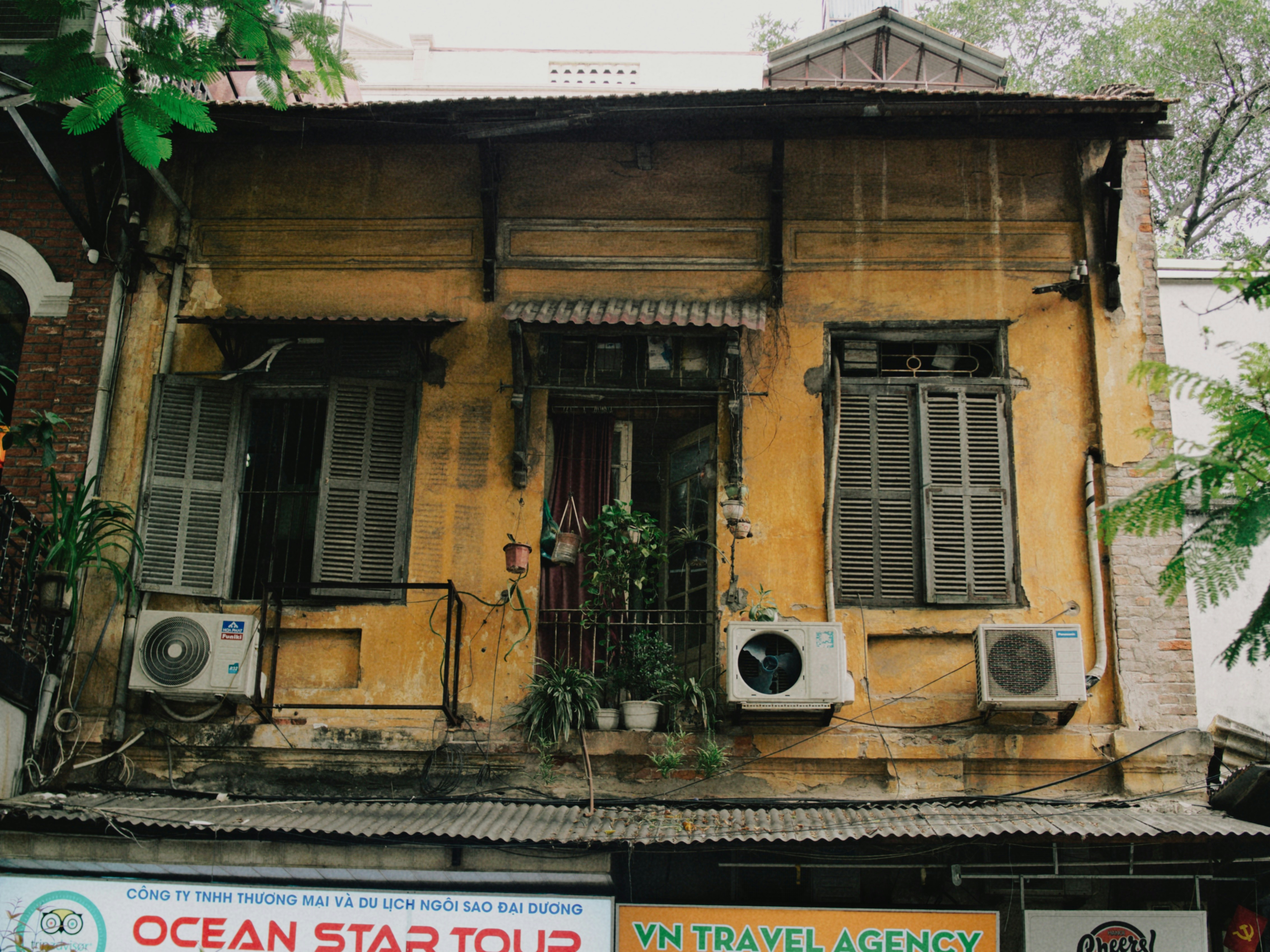 Worn Yellow Facade Overlooked by Air-Conditioners and Shopfront Signage