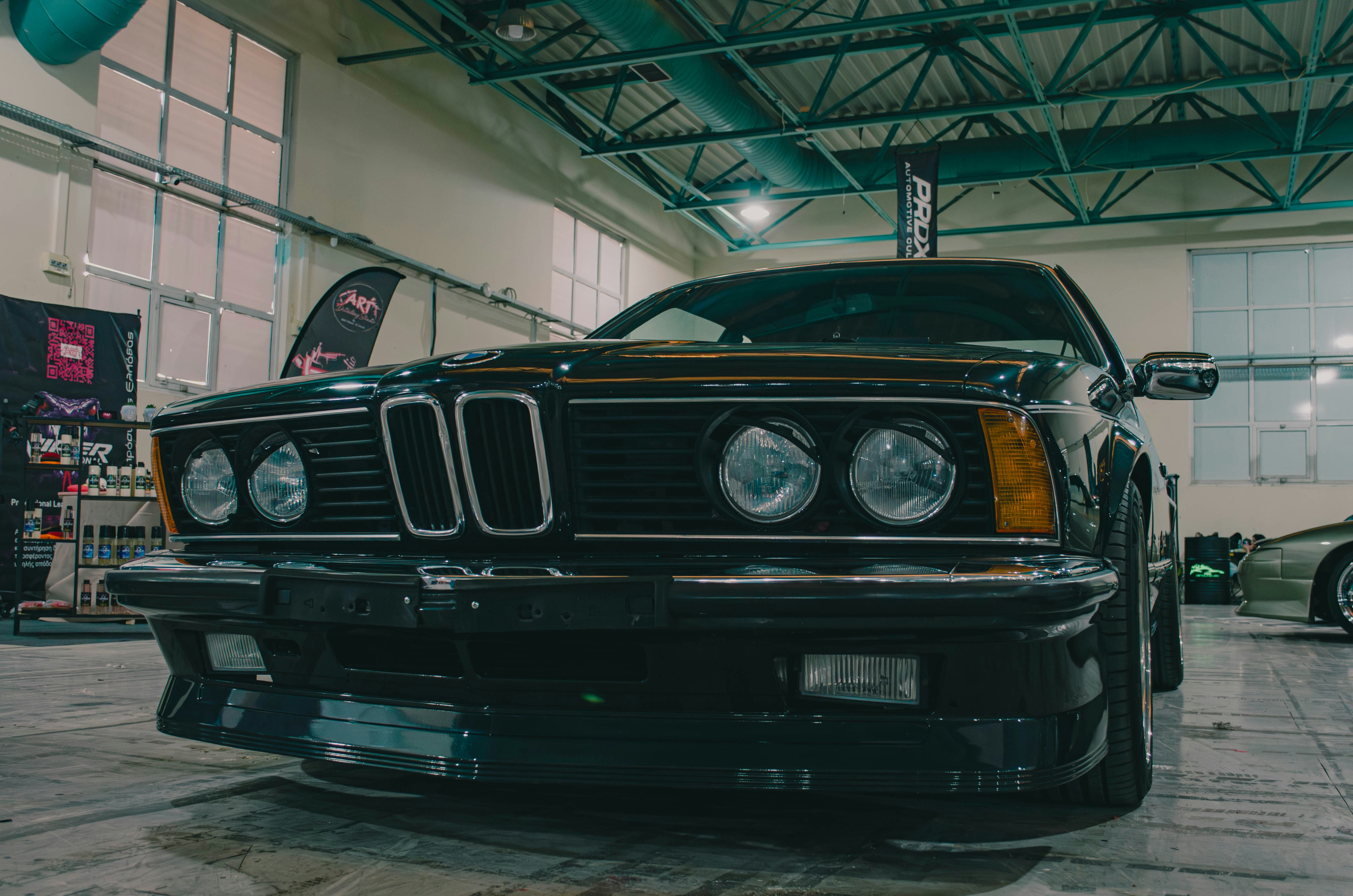Glossy vintage BMW on a showroom floor, captured from a low angle with the front grille and dual round headlights emphasized; indicates a display context, not a street scene.