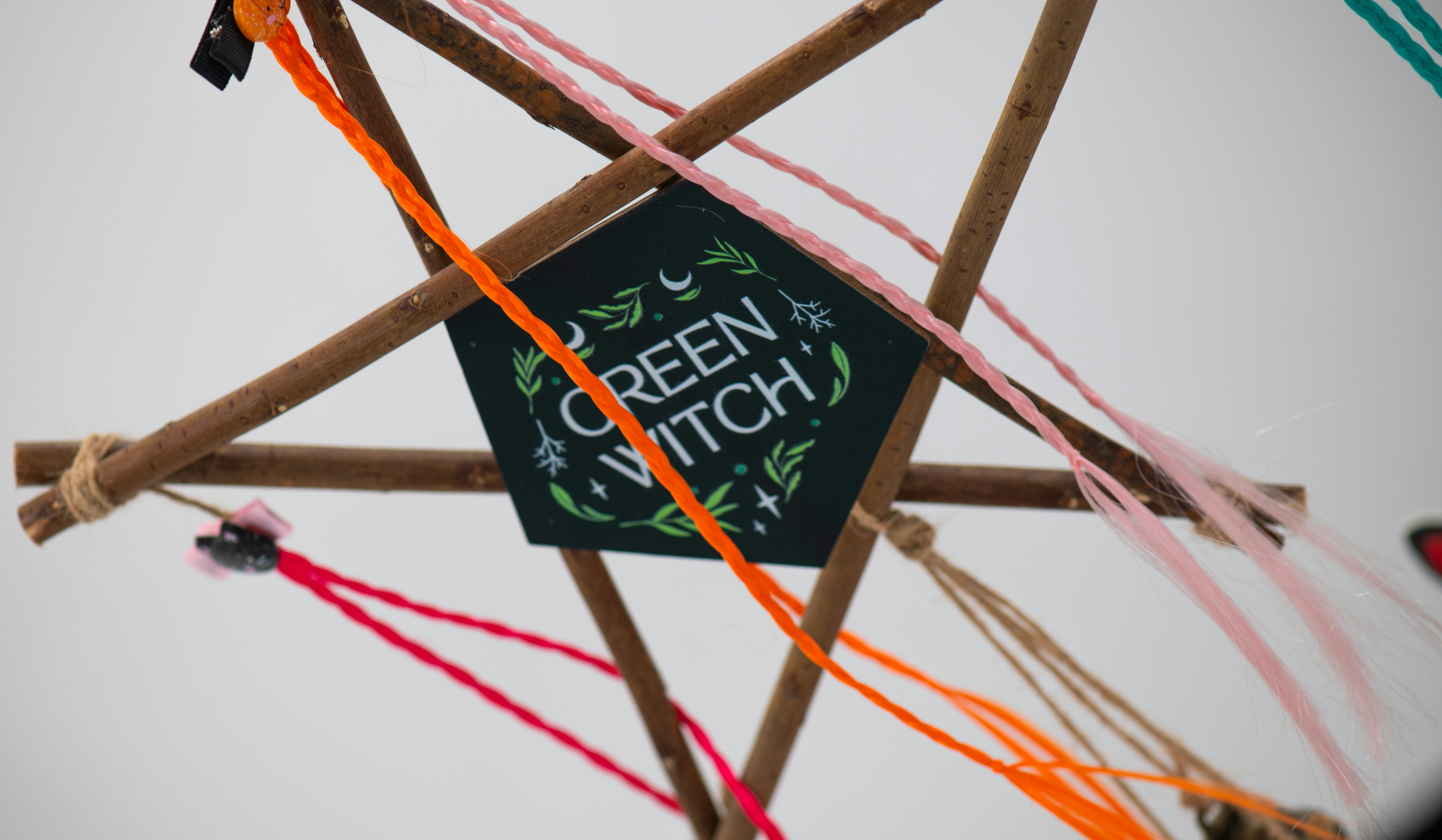 Green Witch Sign Wrapped in Colorful Ribbons Above Wooden Frame