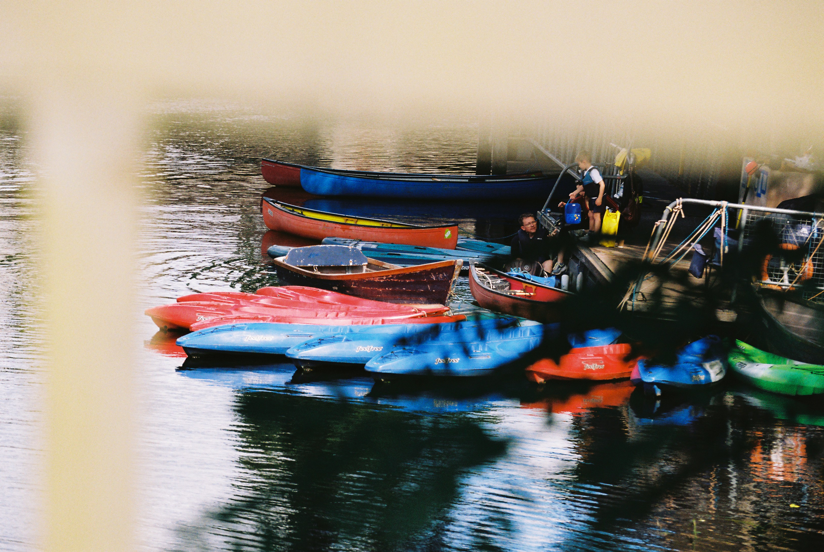 A Row of Colored Kayaks Docked by a Quiet River