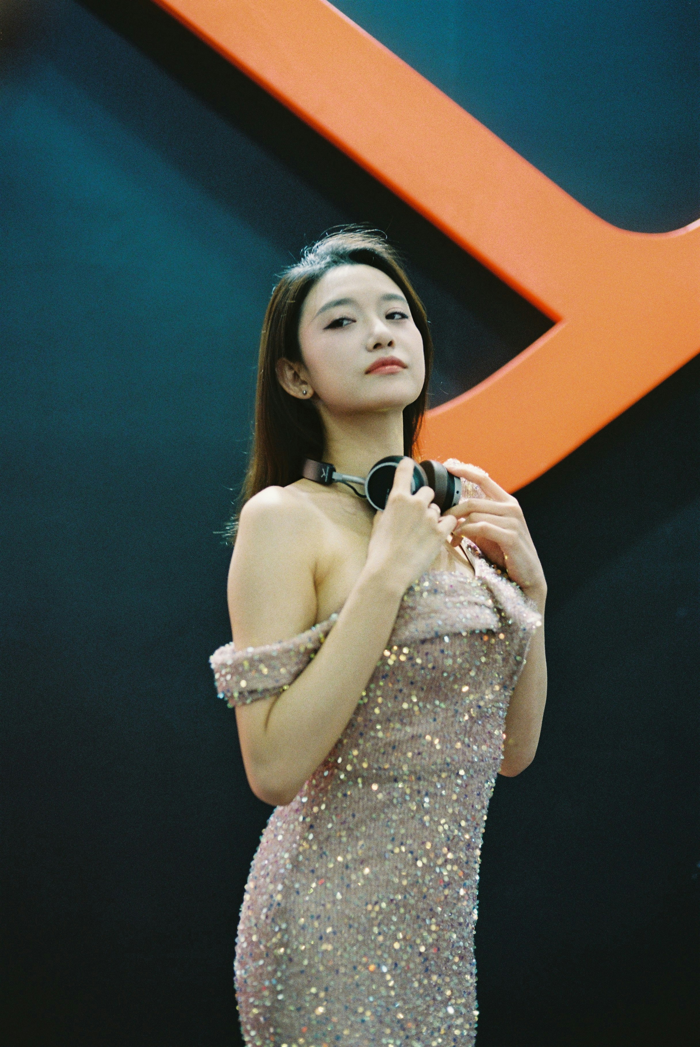 A woman in a sequined dress holding headphones around her neck