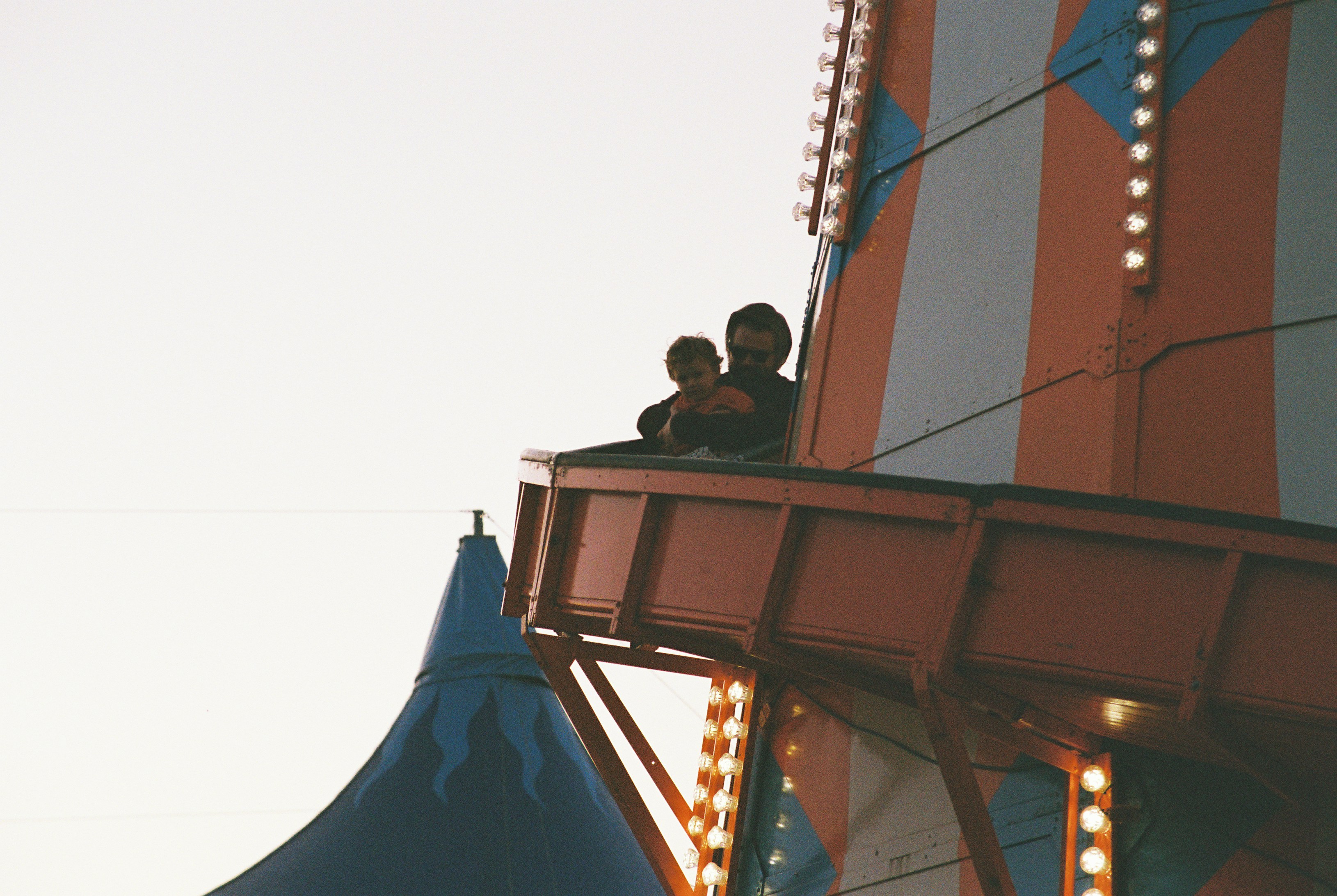 Edge of the Ride: silhouettes on a sunlit carnival platform