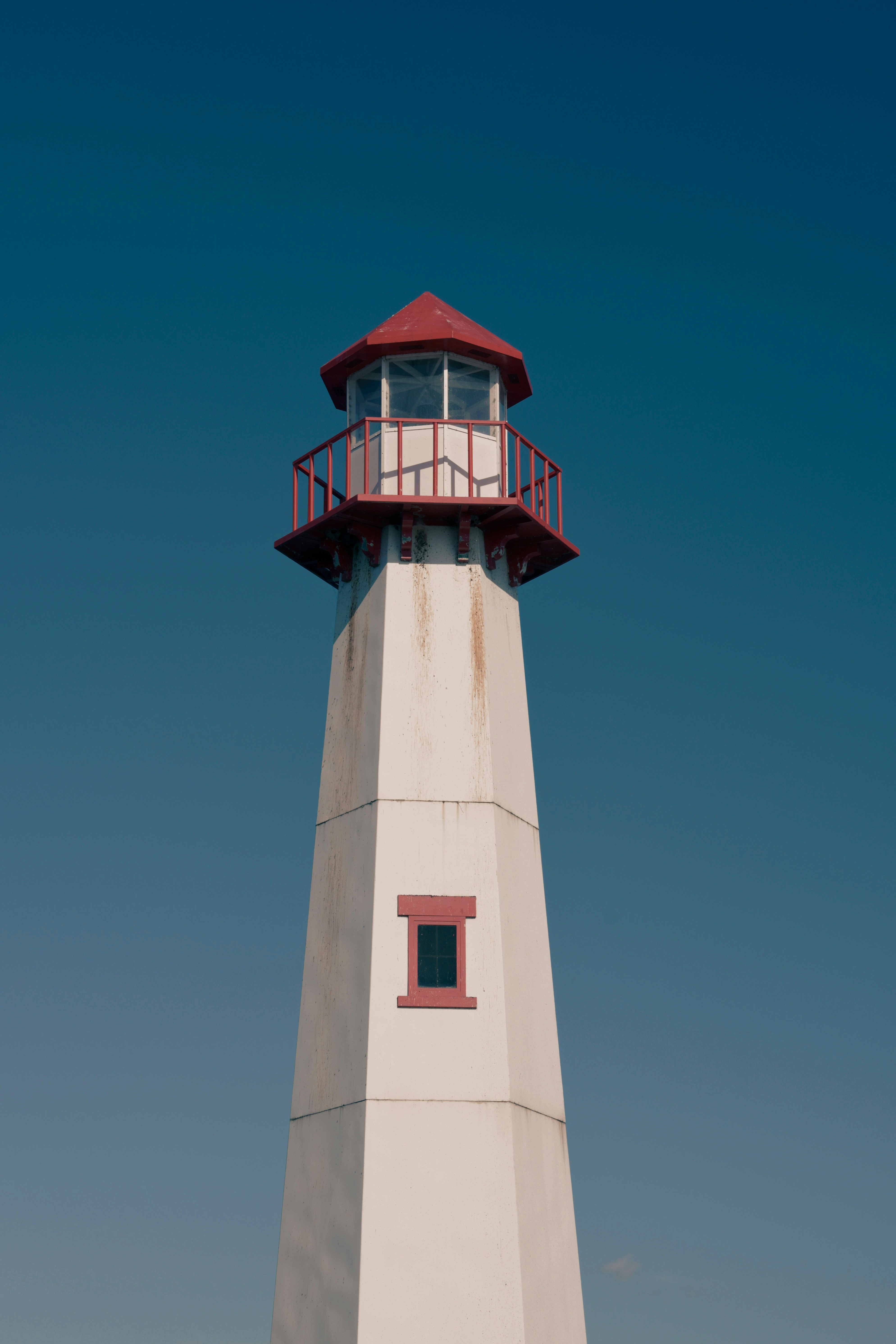 Red beacon under cobalt sky: a solitary lighthouse rising from the sea