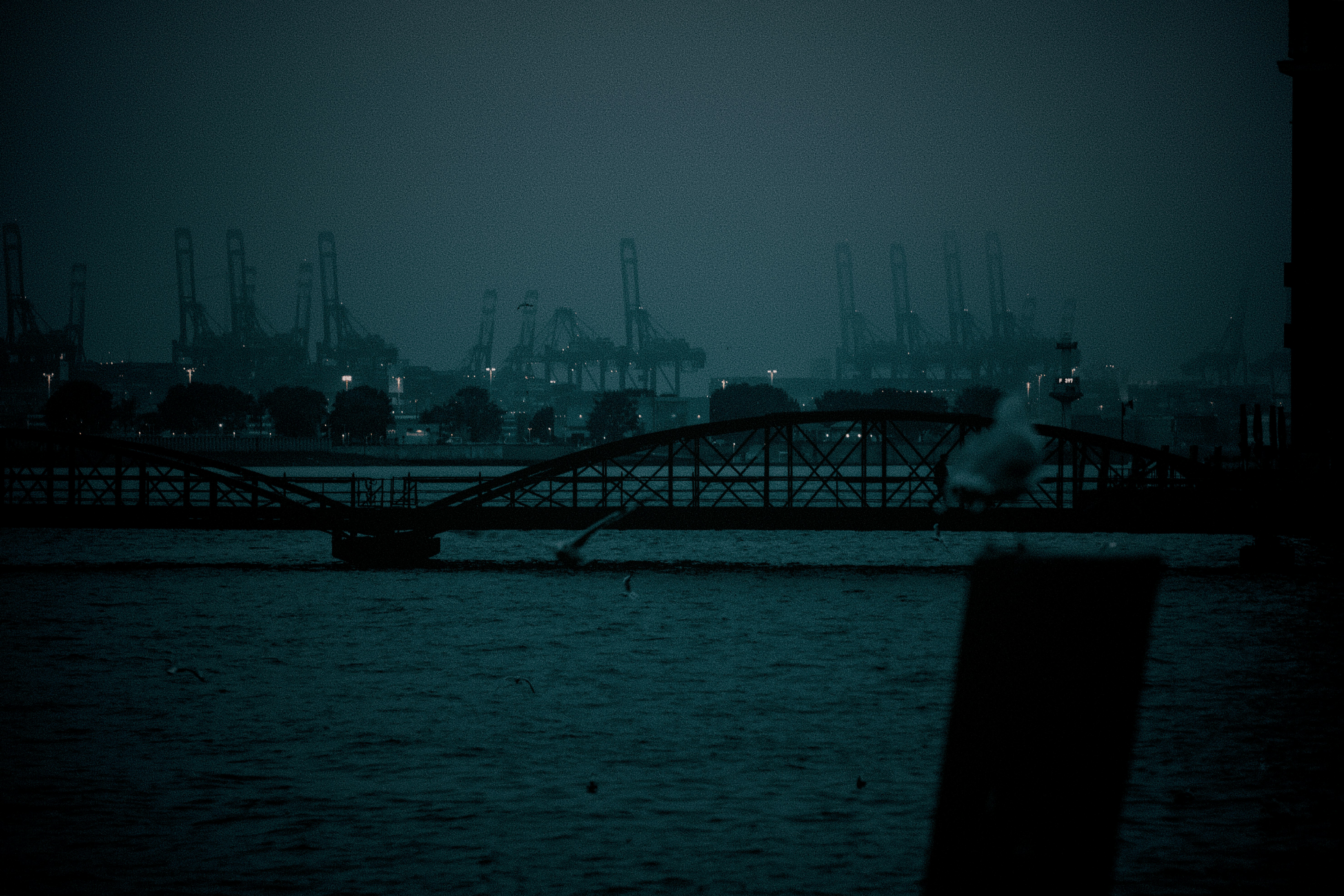 Midnight Harbor: Silhouetted Cranes Beyond a Quiet Bridge