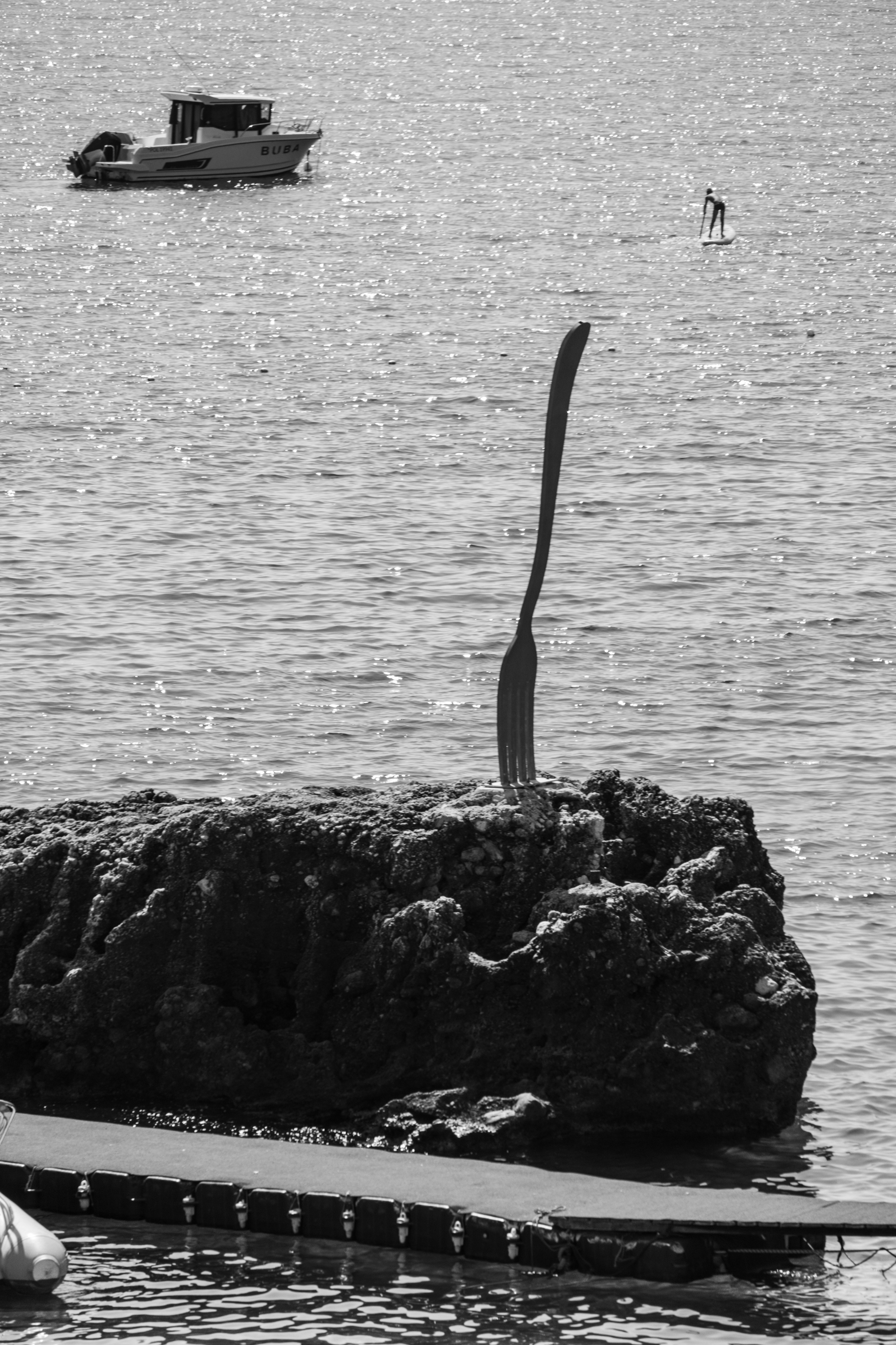 A lone oar Curves Upright on a Rocky Pier under Gentle Sunlight
