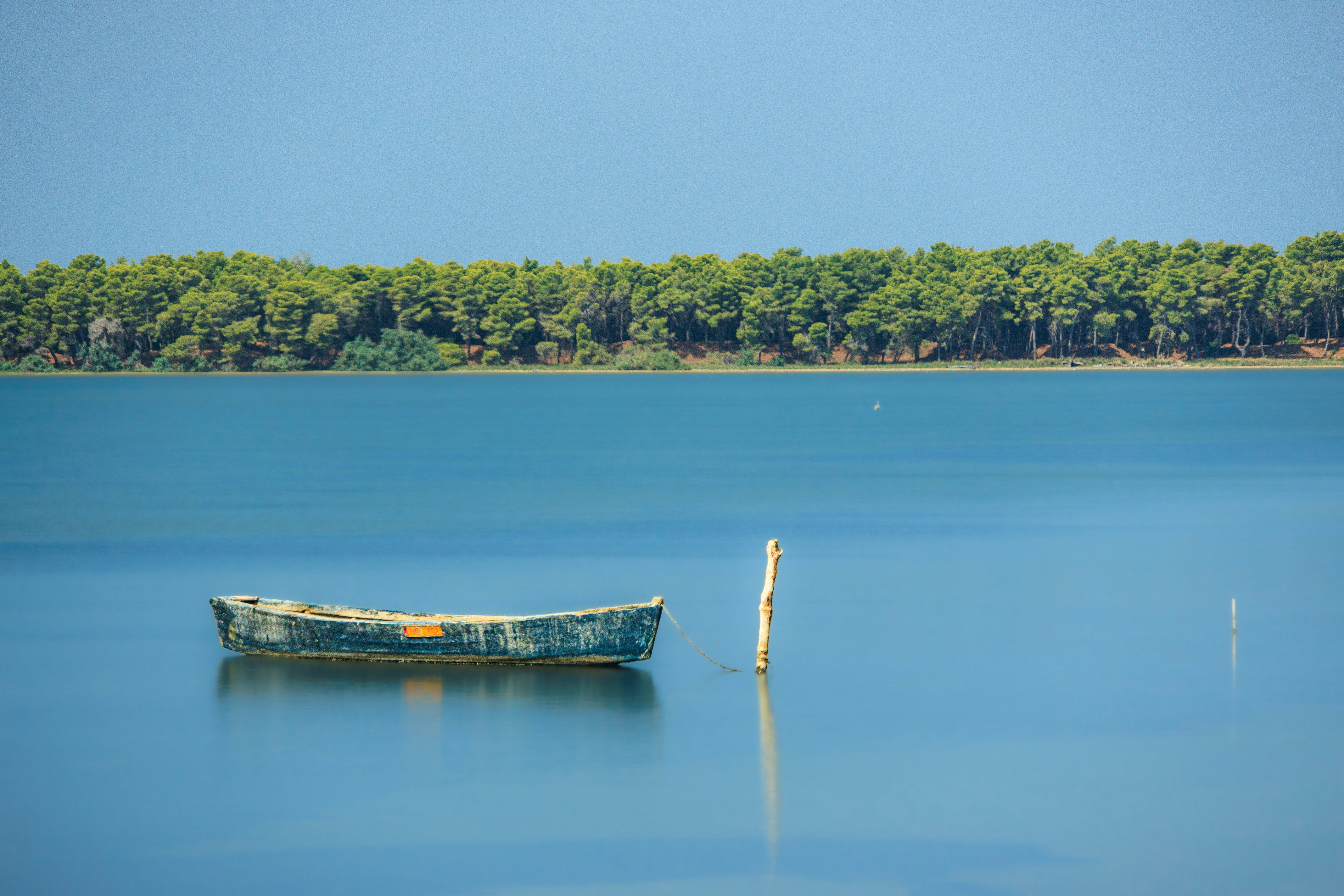 Lonely Boat on a Glassy Tide Under a Linear Horizon