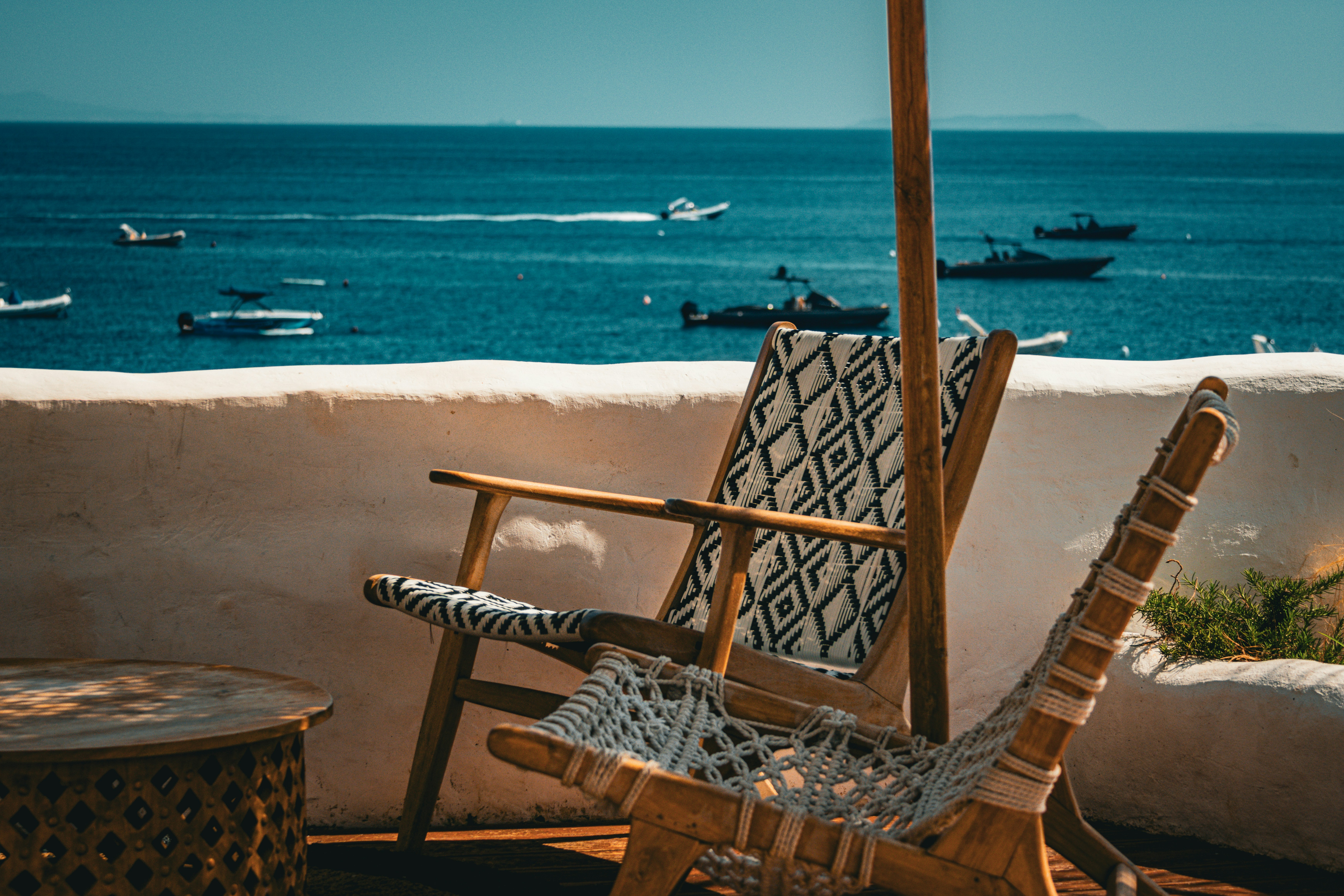 Sunlit Porch by the Sea: Wooden Chairs and Waving Boats