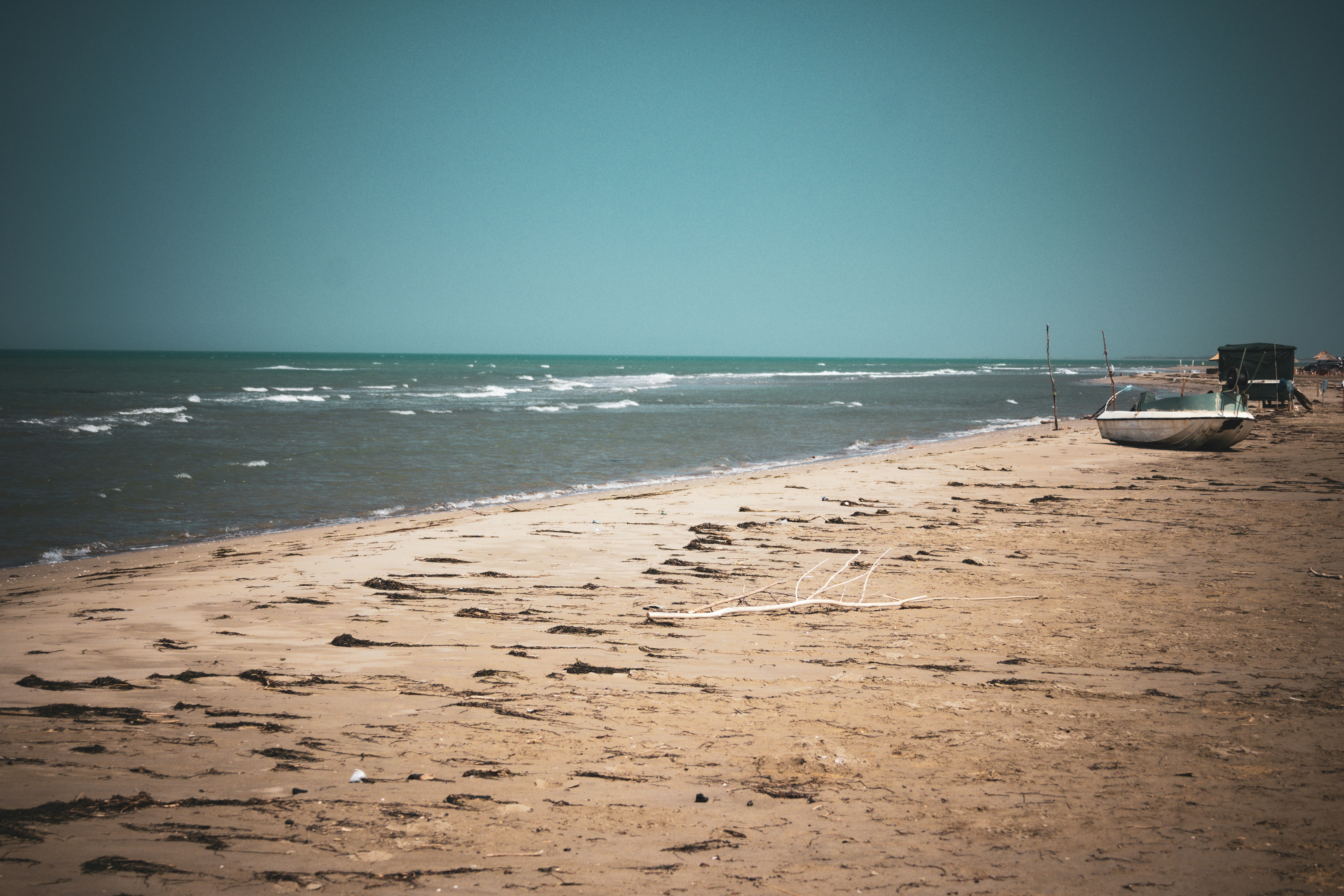 Deserted shoreline under a pale turquoise sky