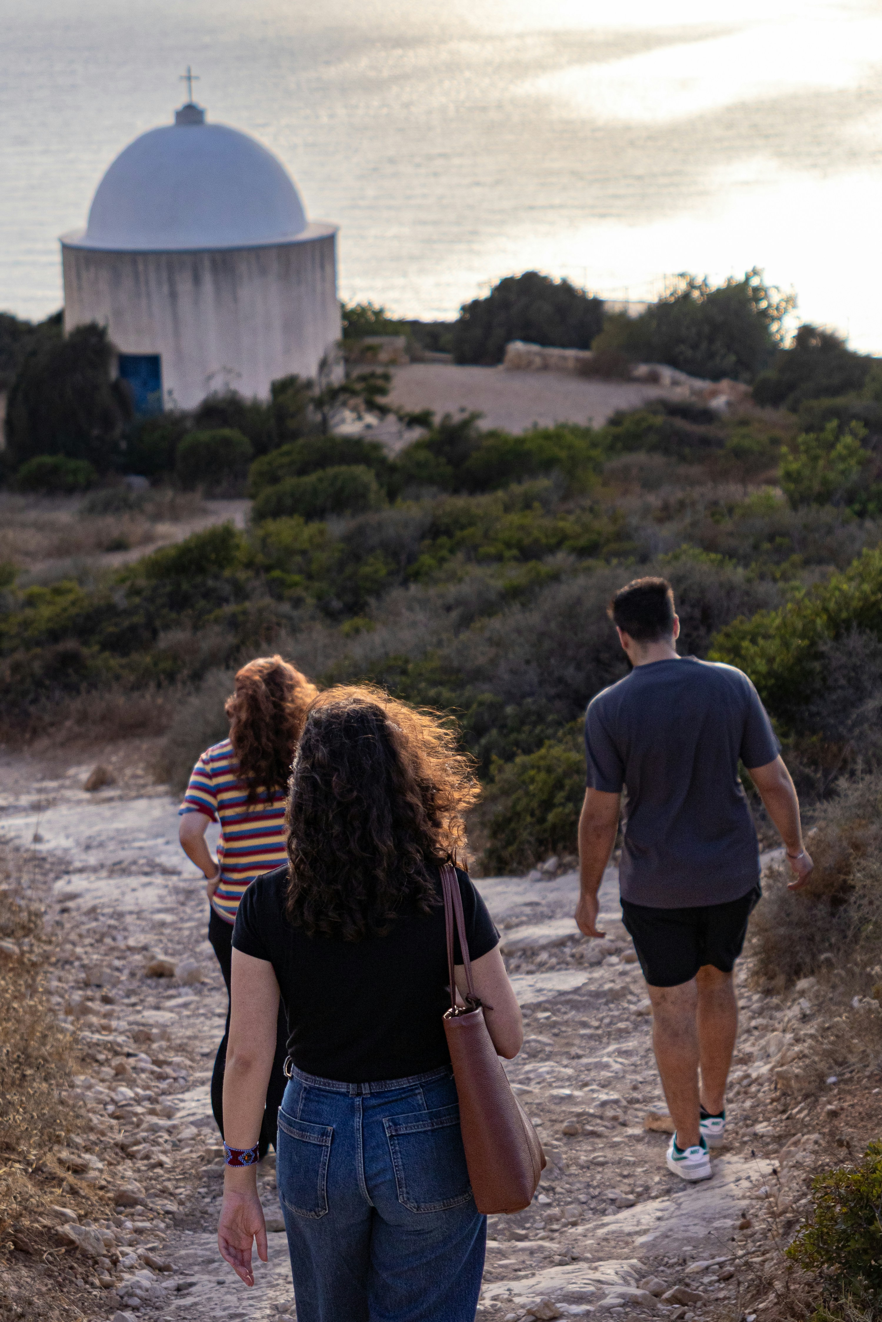 Path to the white-domed chapel: a group ascends the coastal trail at golden hour