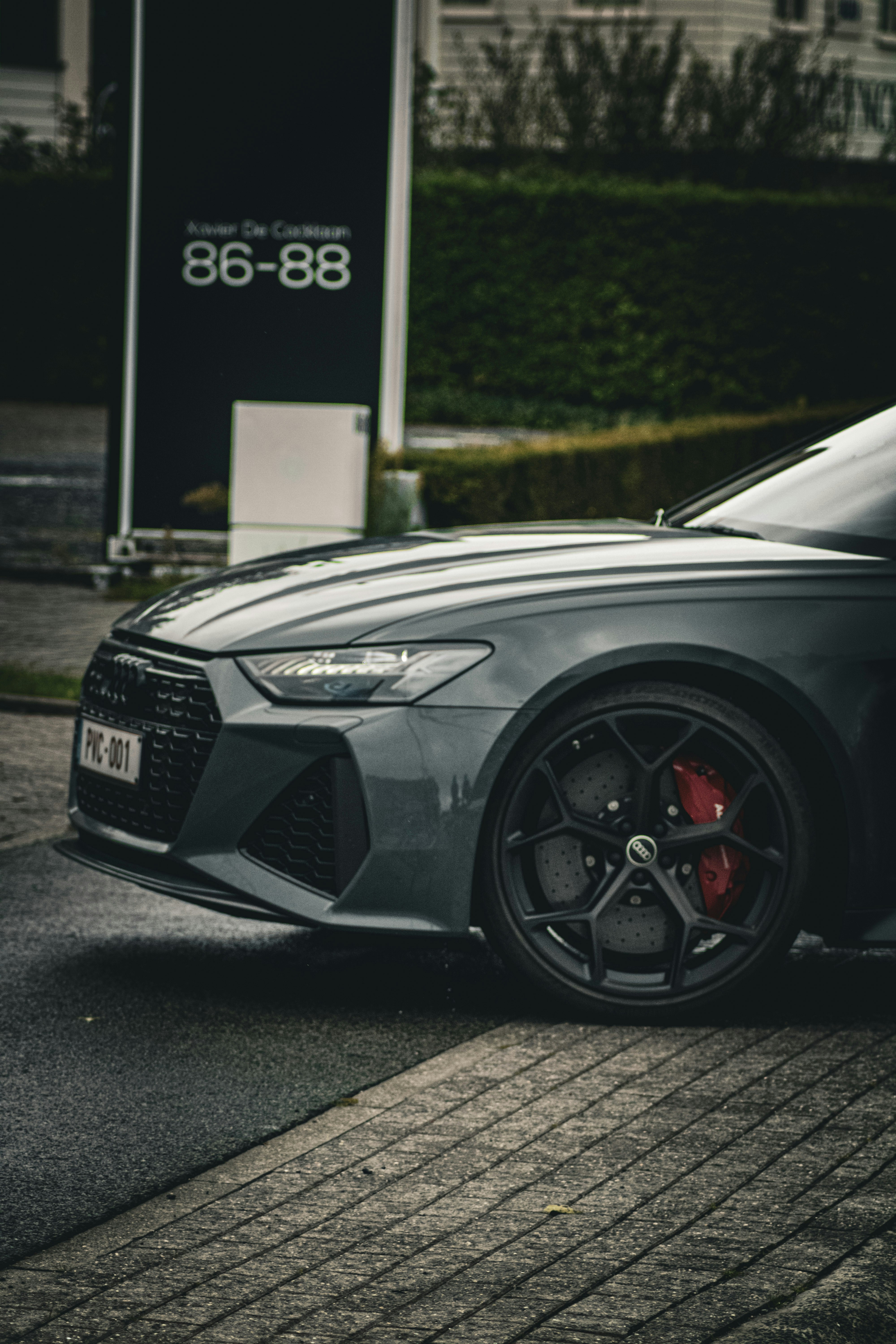 Low-angle glimpse of a grey Audi RS with red brake calipers at the showroom edge