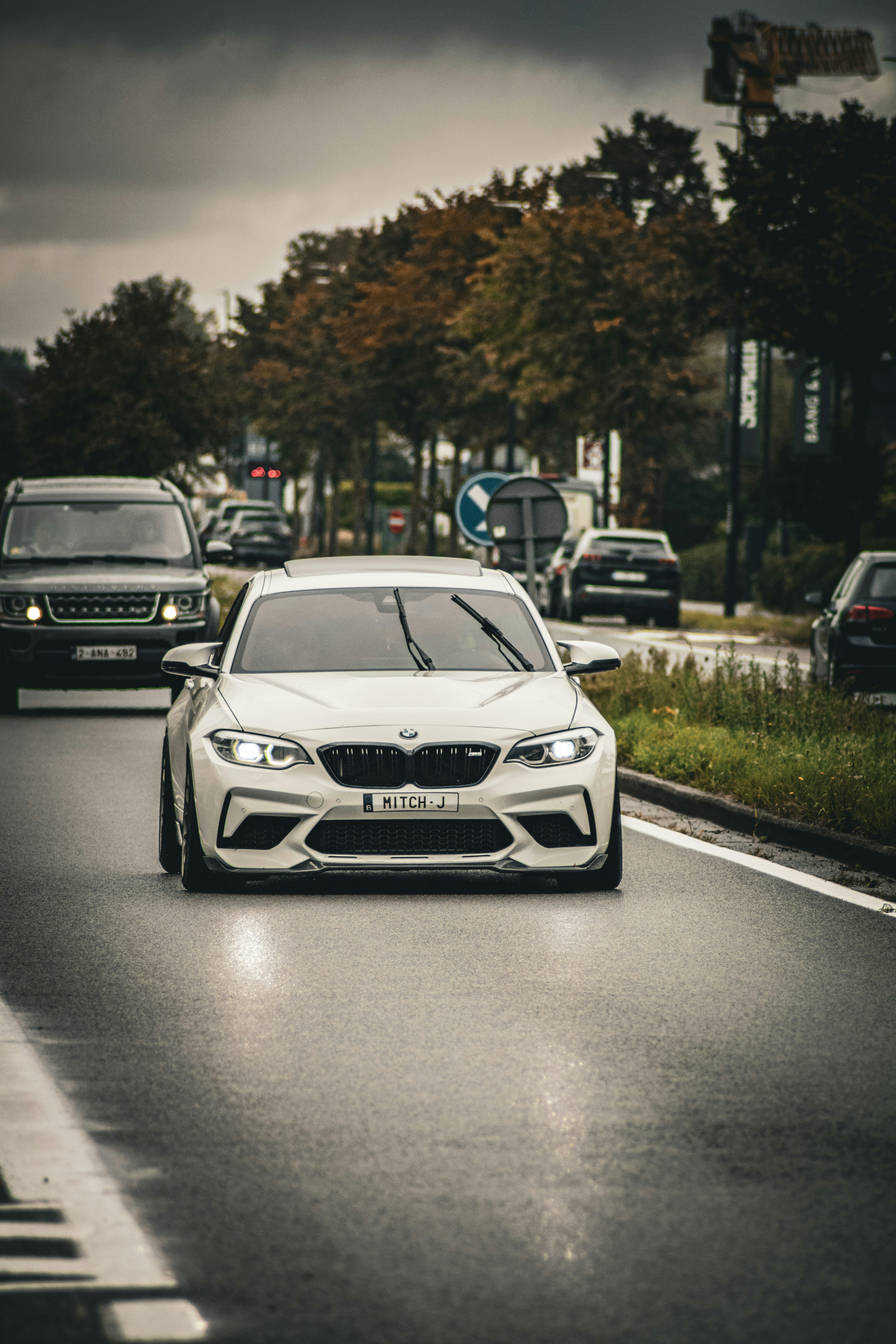 Midfield Power: A White BMW Leads the Rain-Slicked Street