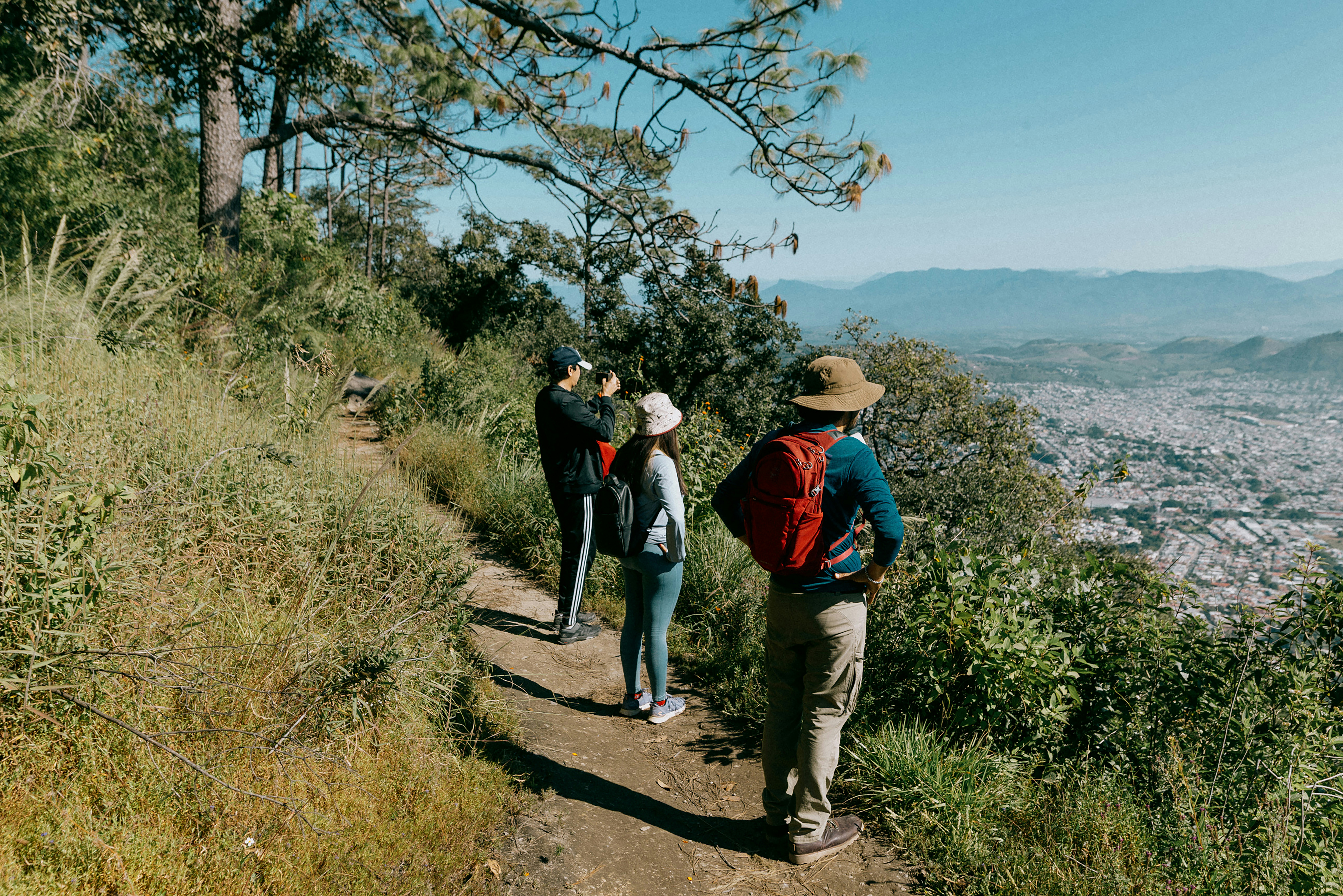 Hikers on a Ridge Trail Overlooking a Valley Cityscape