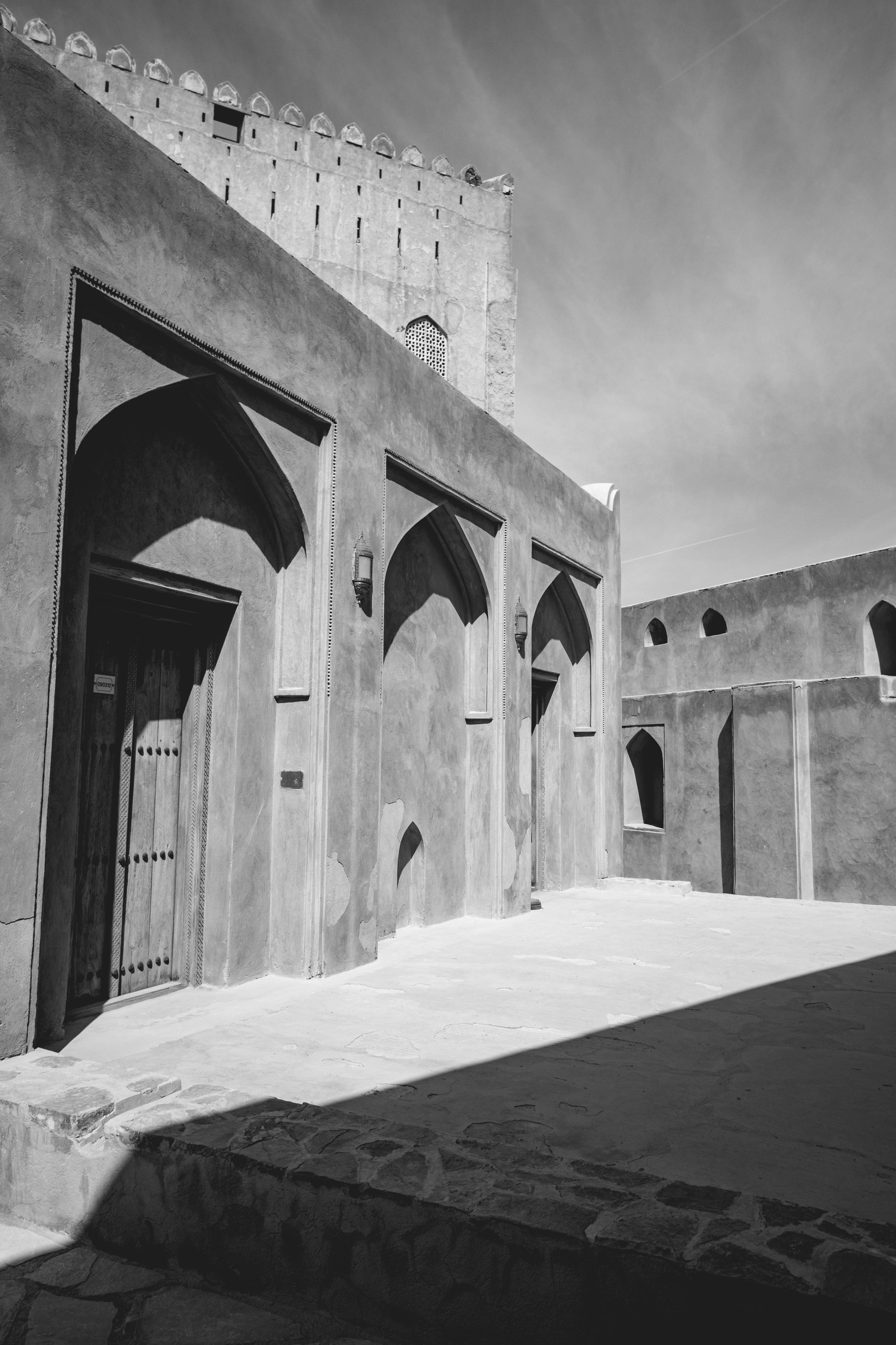 Arched Facades and Shadowed Courtyard under a Desert Sky