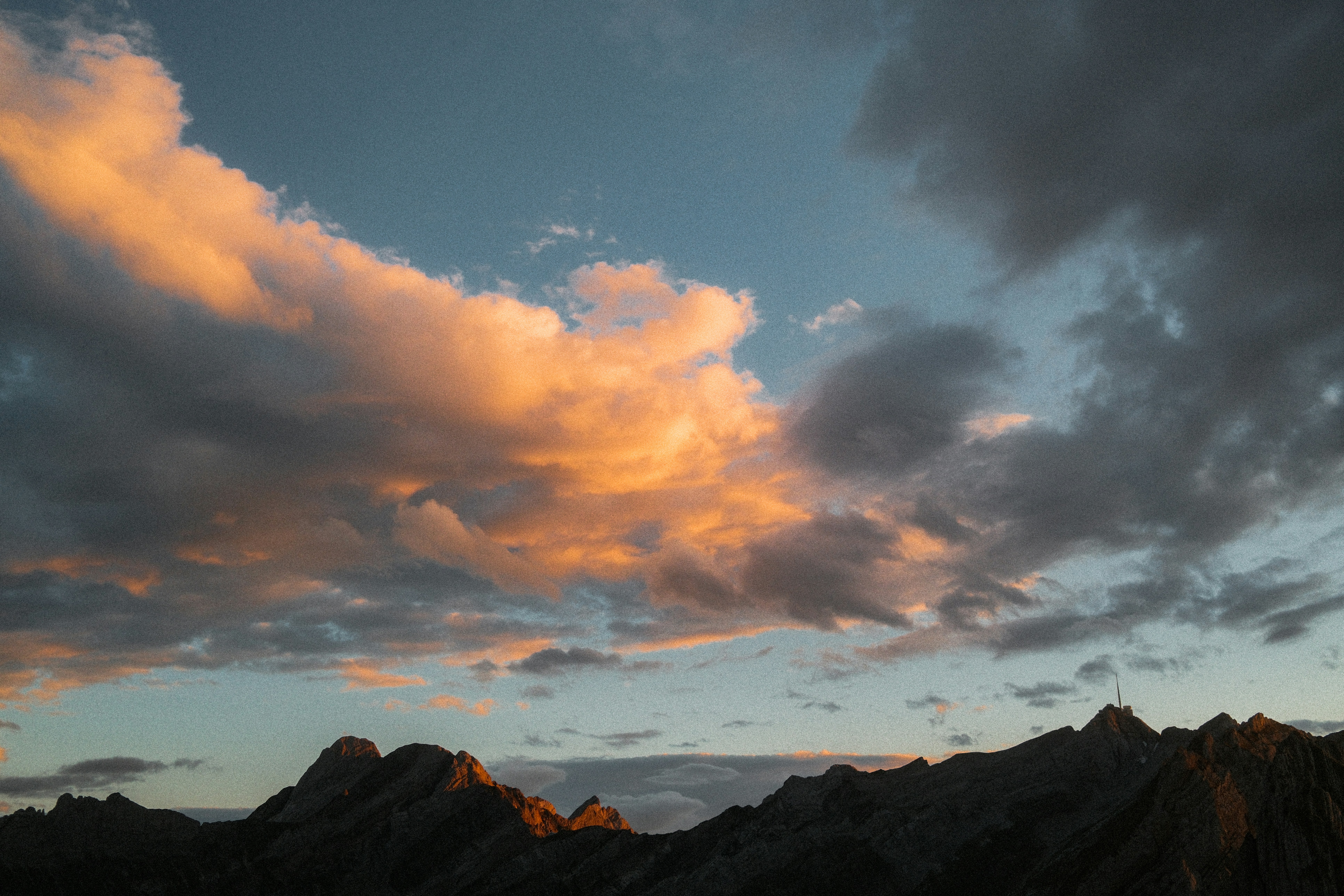 Golden Clouds Over Jagged Peaks at Dusk