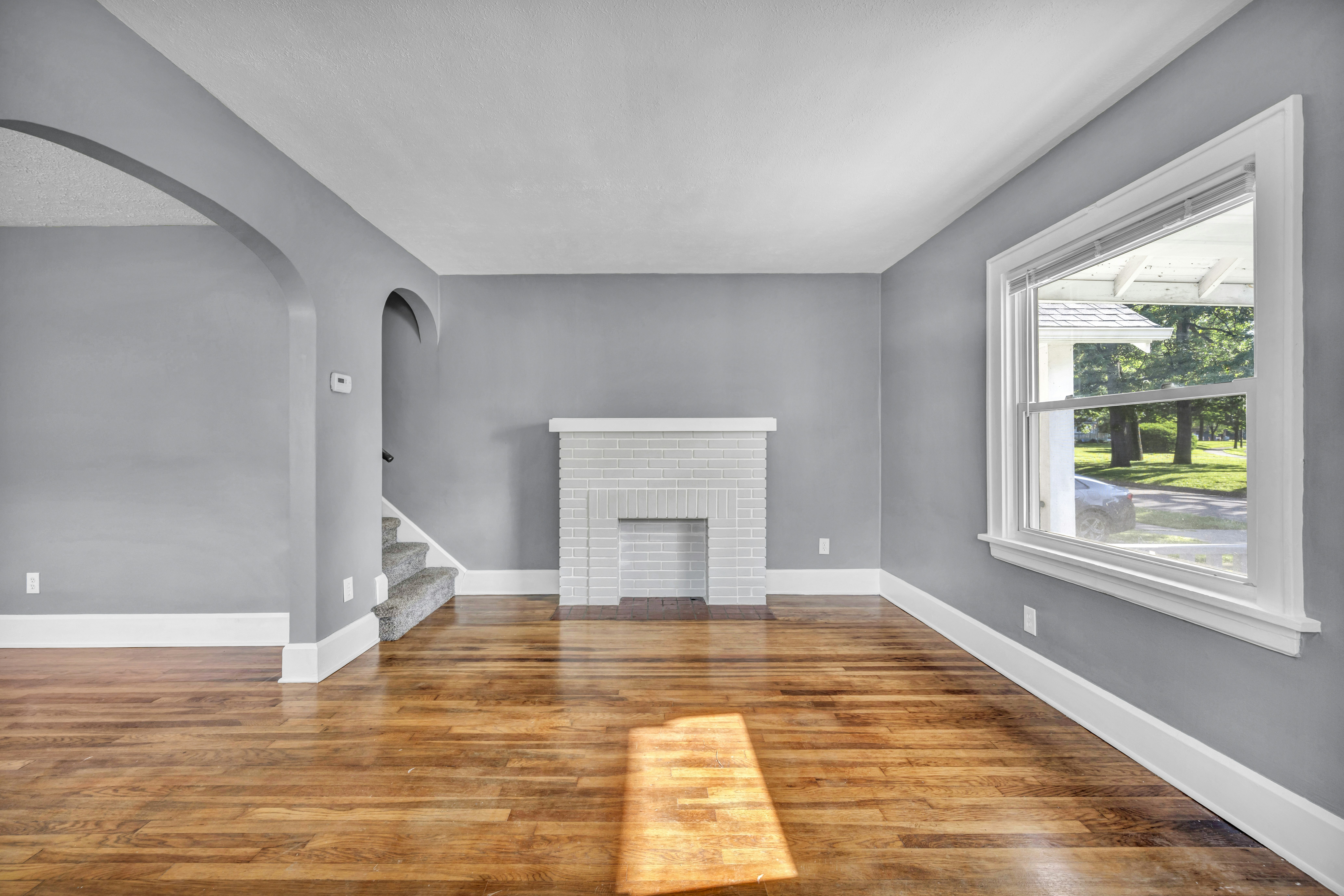 Sunlit Living Room with Centered Fireplace and Large Window View