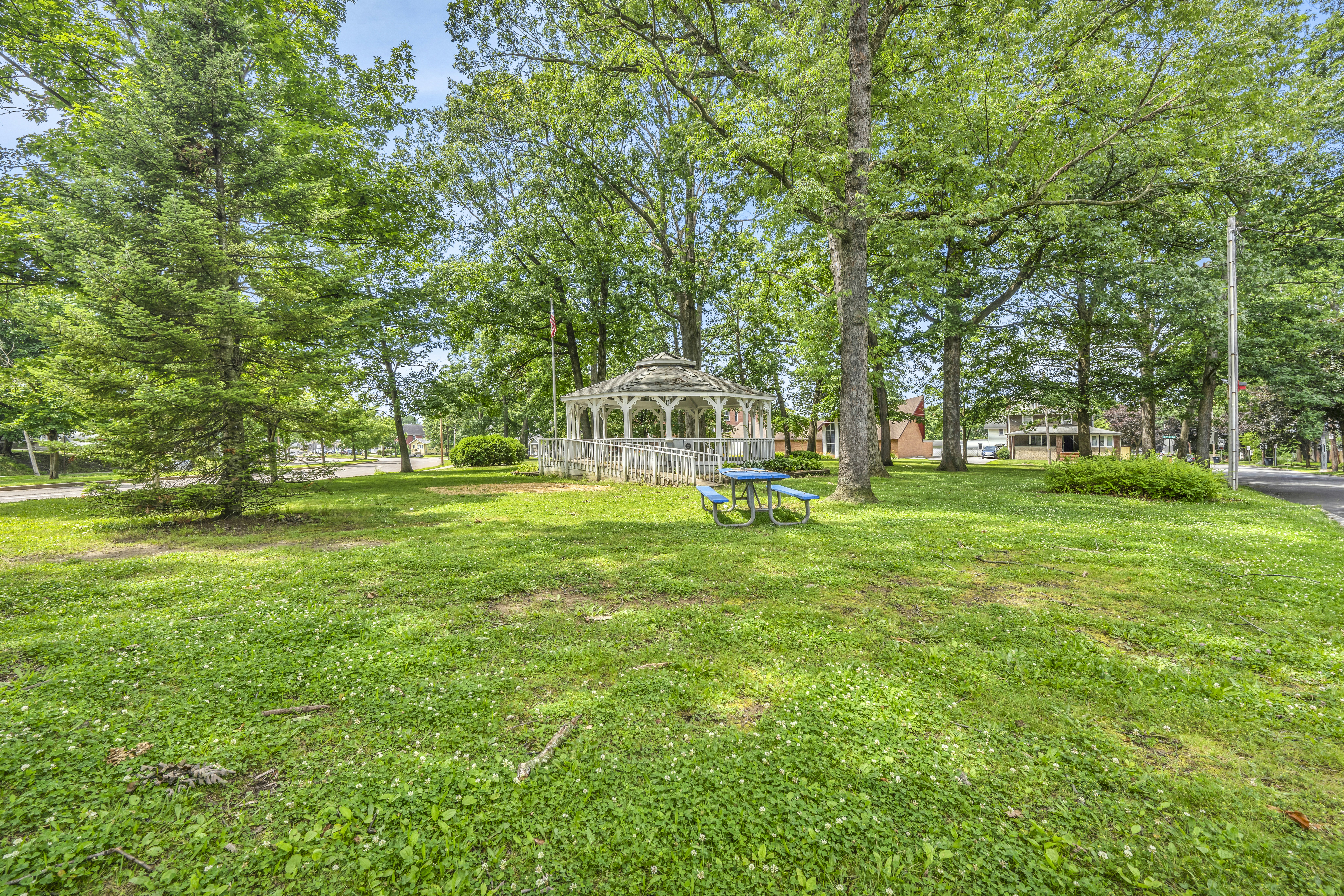 Sunlit gazebo centerpiece framed by a green canopy