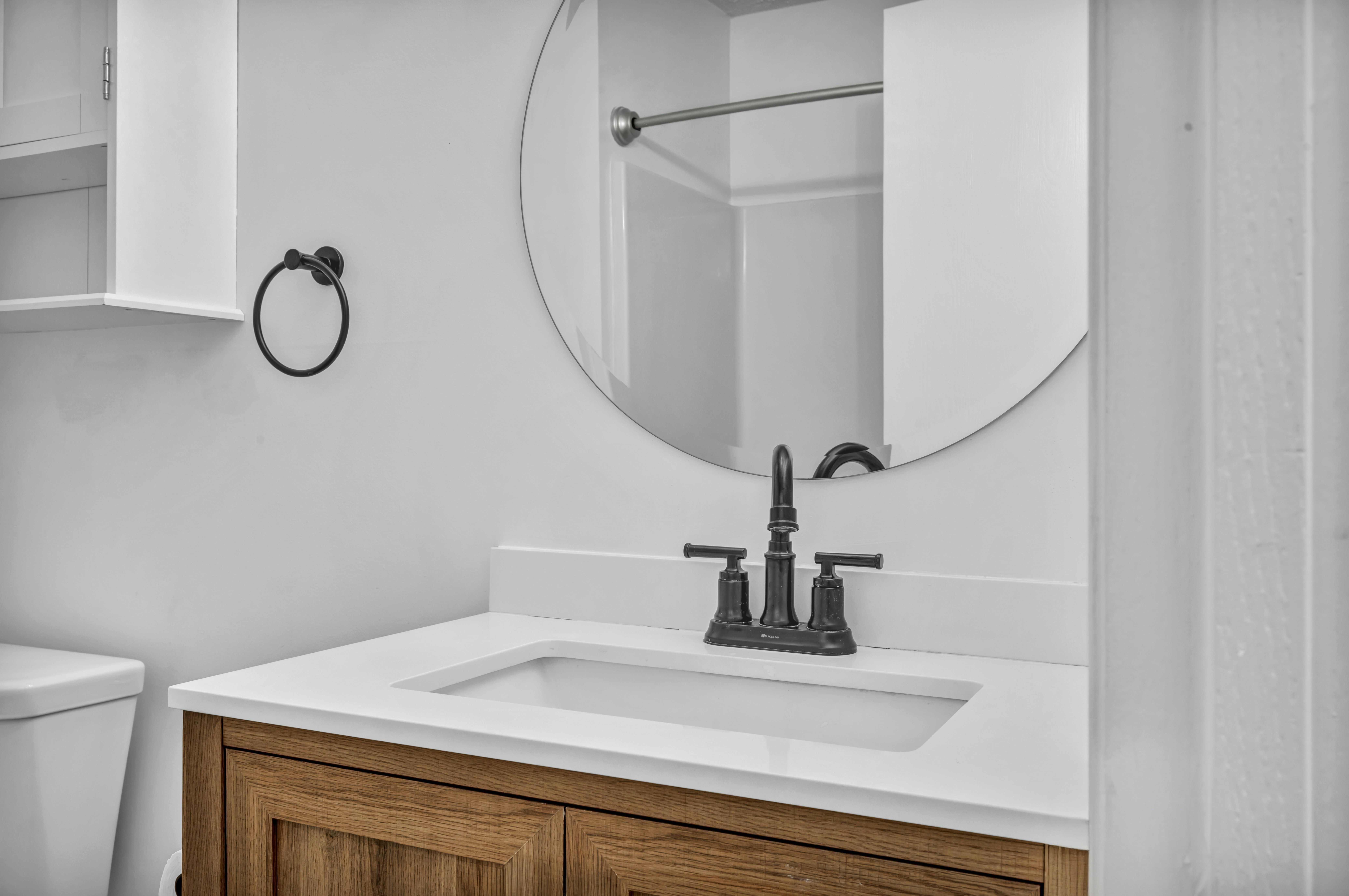 Wooden Vanity Beneath a Round Mirror in a Minimal Bathroom