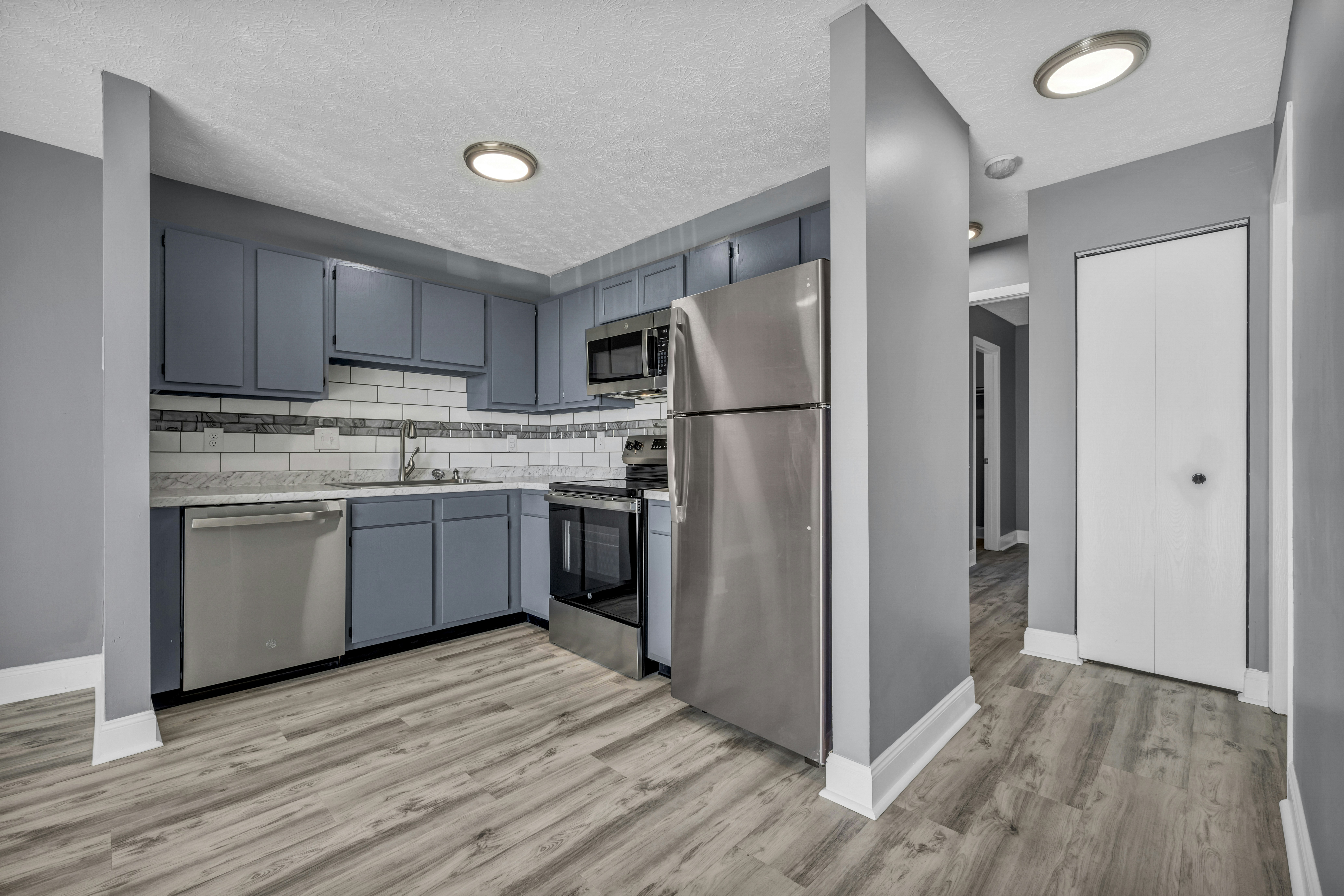 Cozy modern kitchen with steel appliances and blue-gray cabinetry