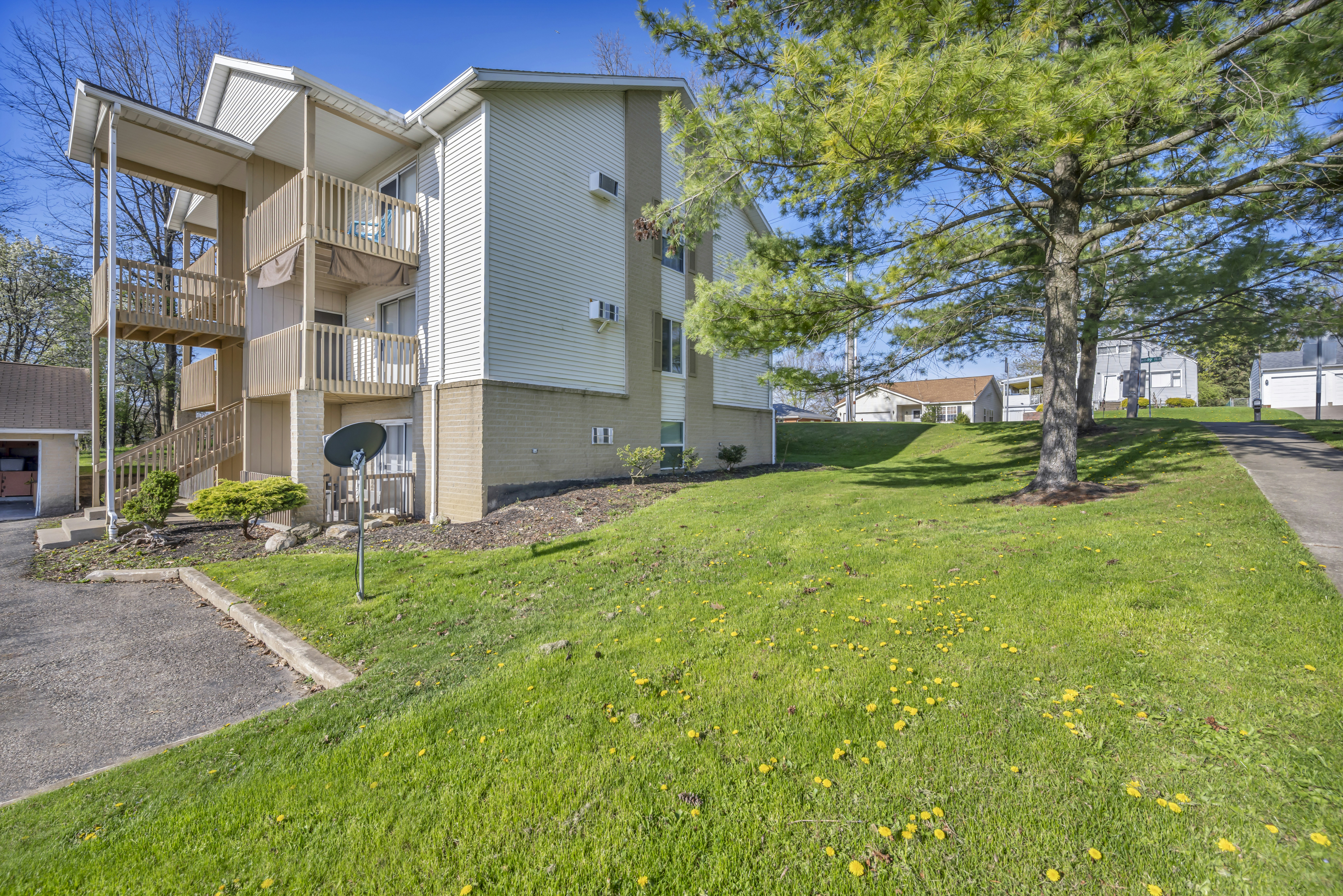 Sunlit Apartment Building with Lush Lawn and Tree-lined Path