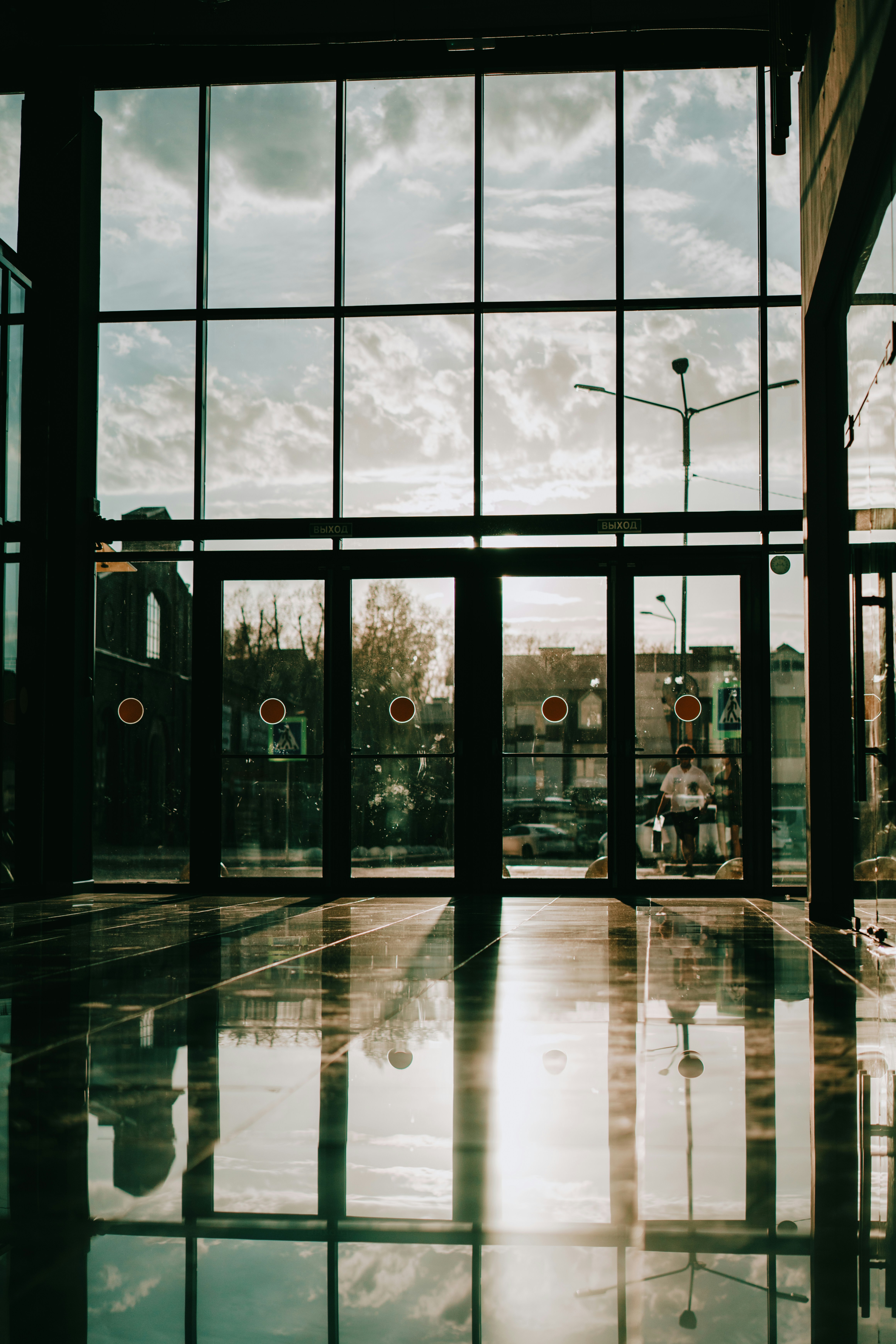 A glass doorway reflecting a sunlit street with people walking outside