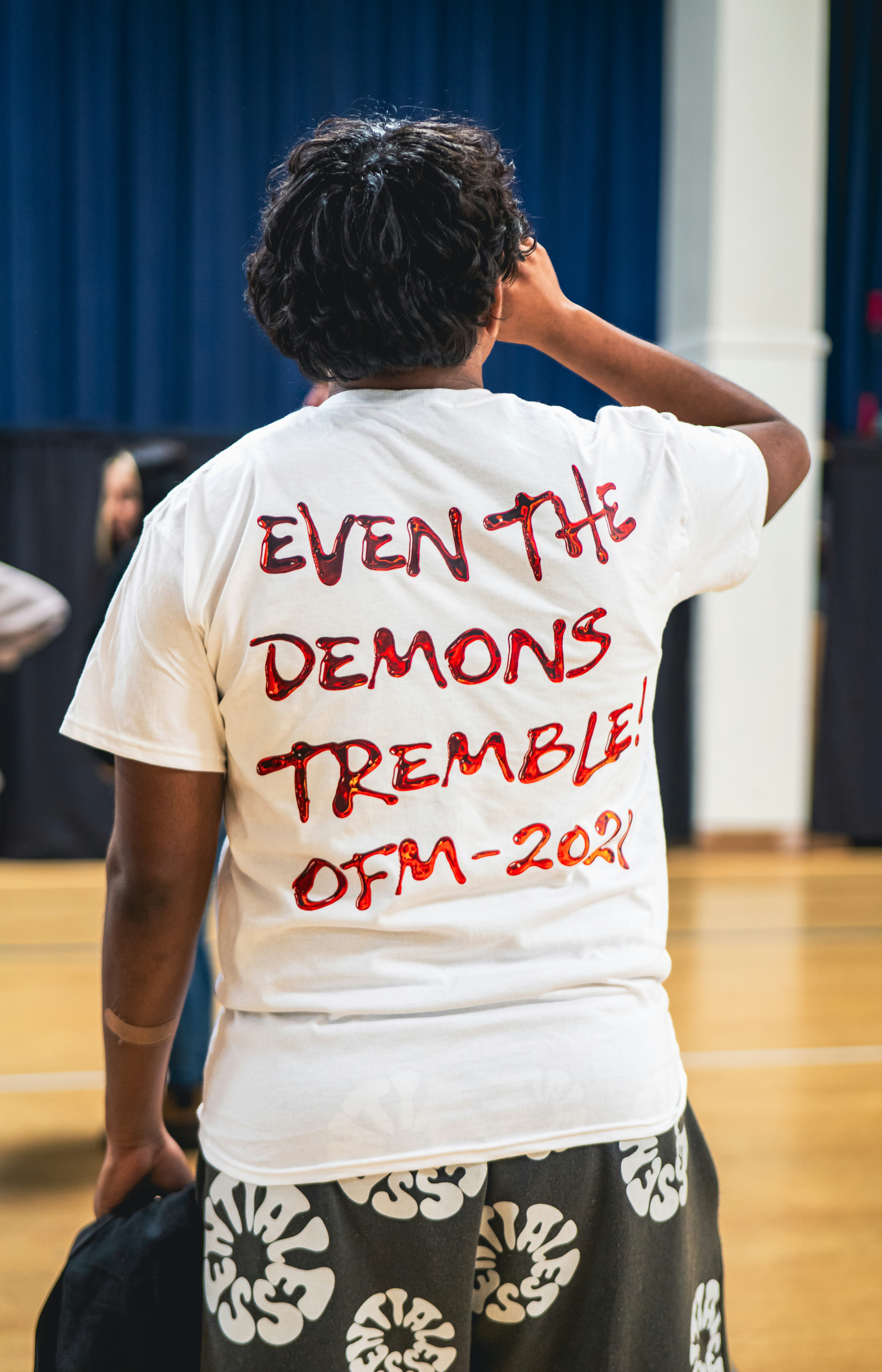Backstage Message: The Shirt Reads 'Even the Demons Tremble' in a Gym Setting