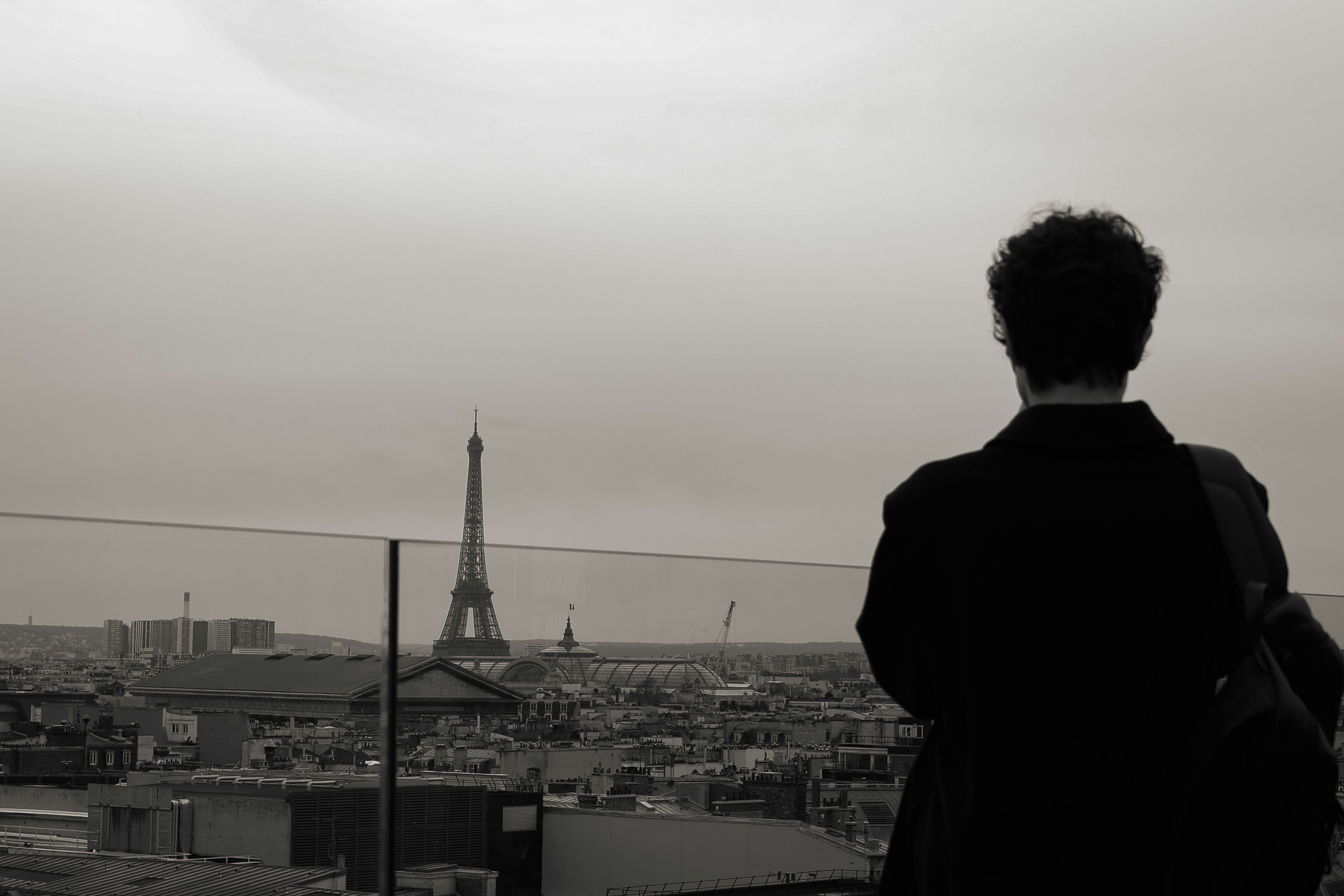Silhouette over Paris: A watcher in the foreground with the Eiffel Tower faint on the horizon