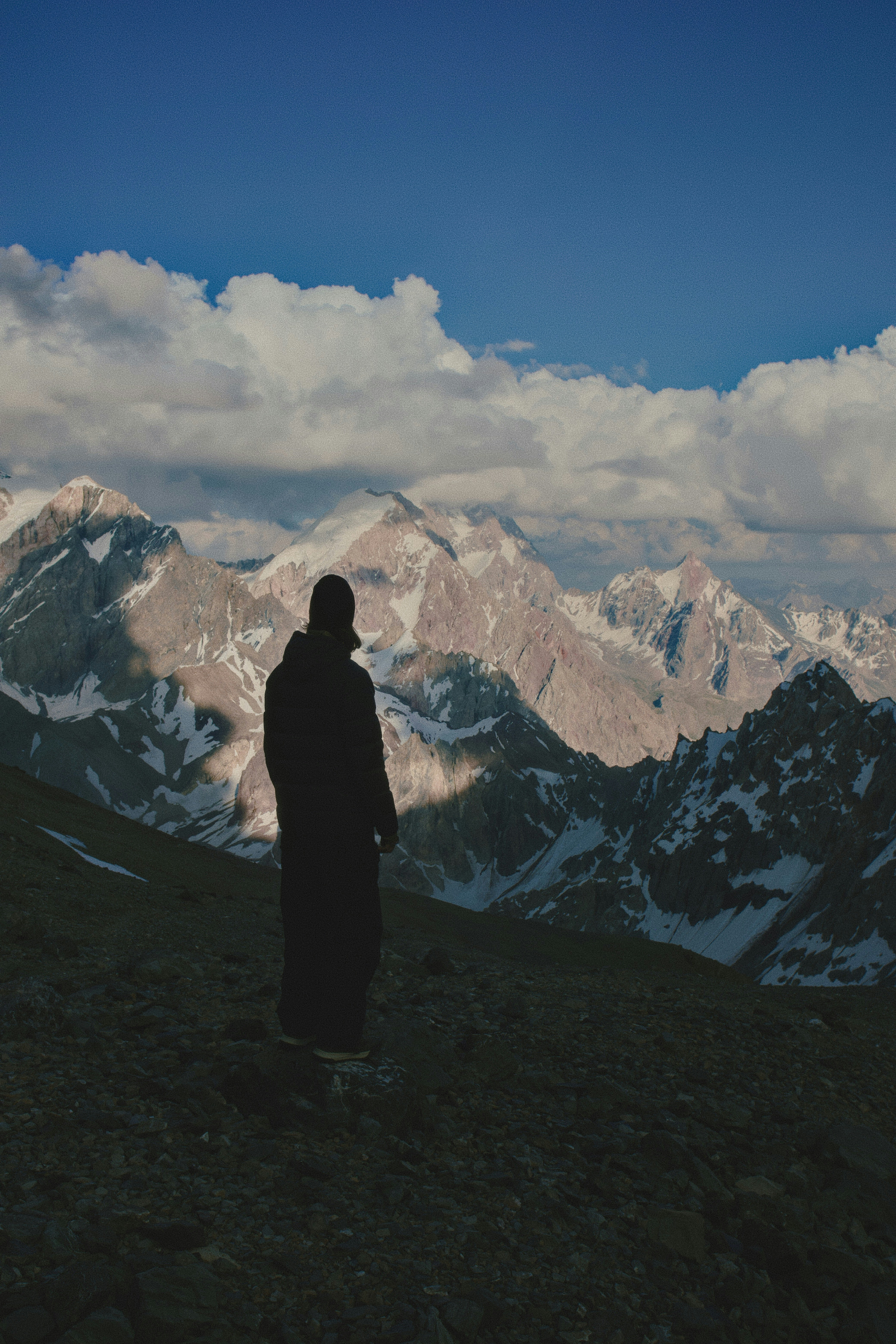 Shadowed Traveler at the Edge of Snow-Laced Peaks