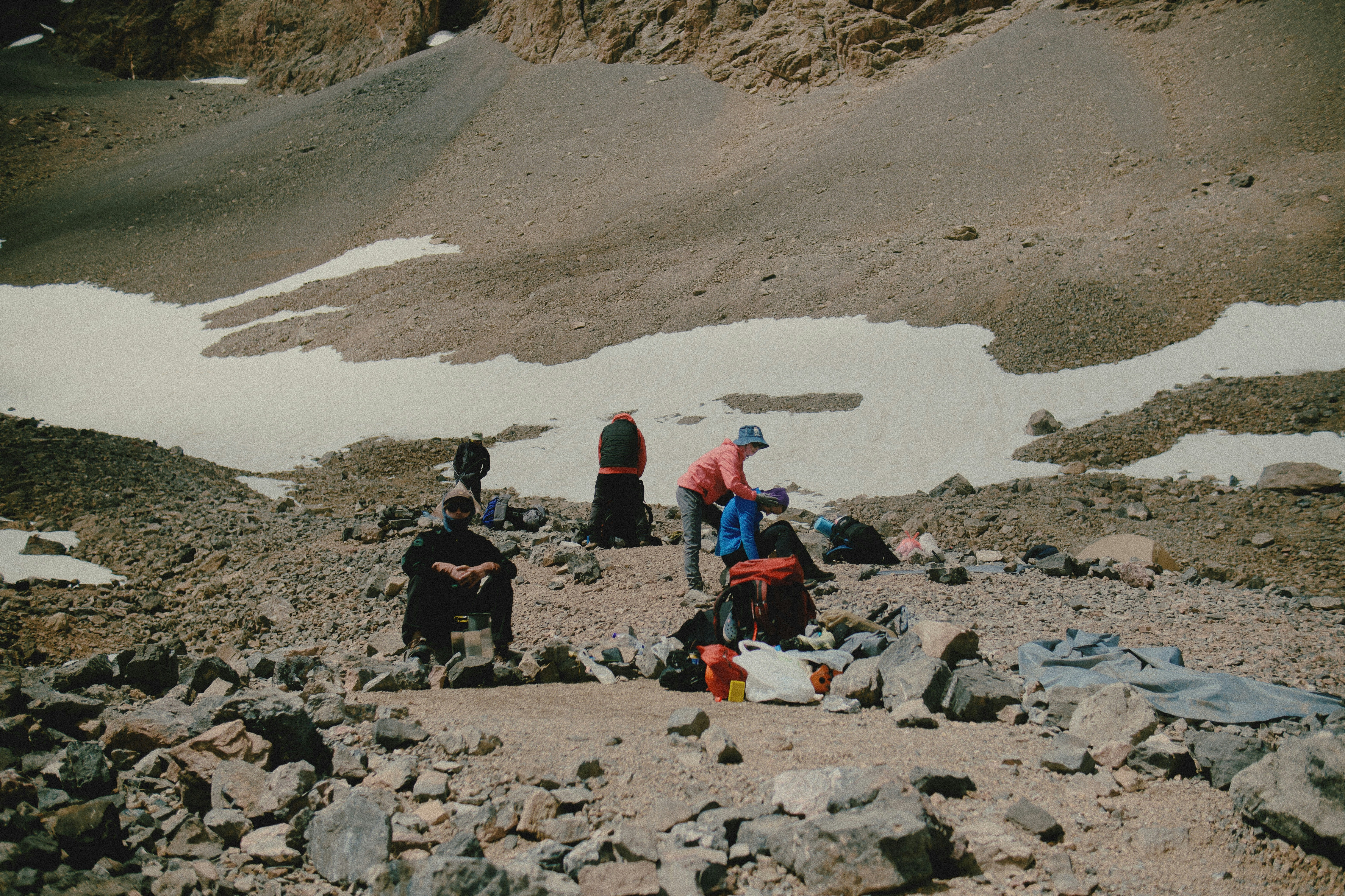 Craggy Camp: Alpine Adventurers Amid Snow Patches