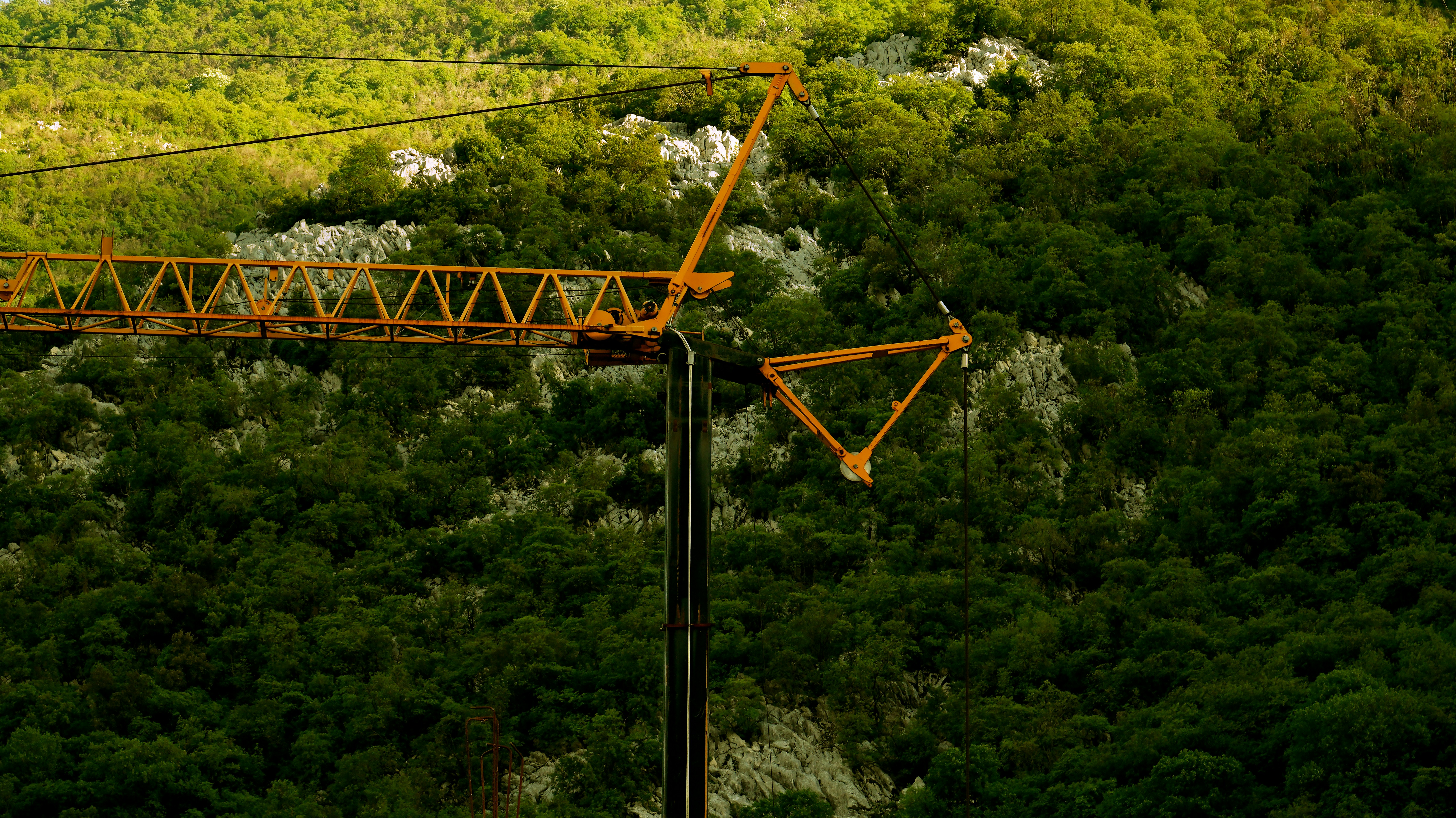 Orange Construction Crane Span Crossing a Forested Slope