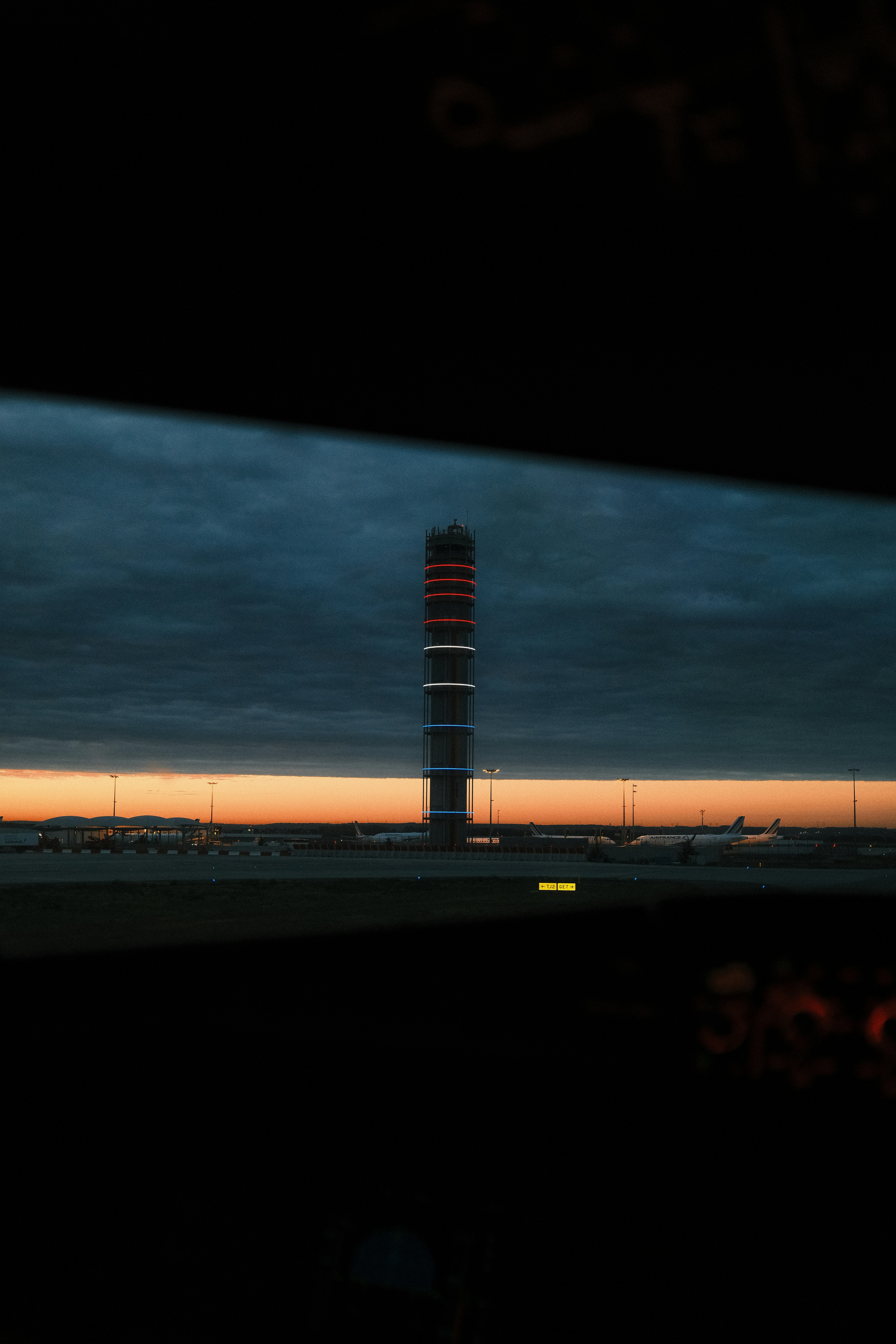 Towering Signal Amid Dusk: A Quiet Airport Tower Through a Car Window