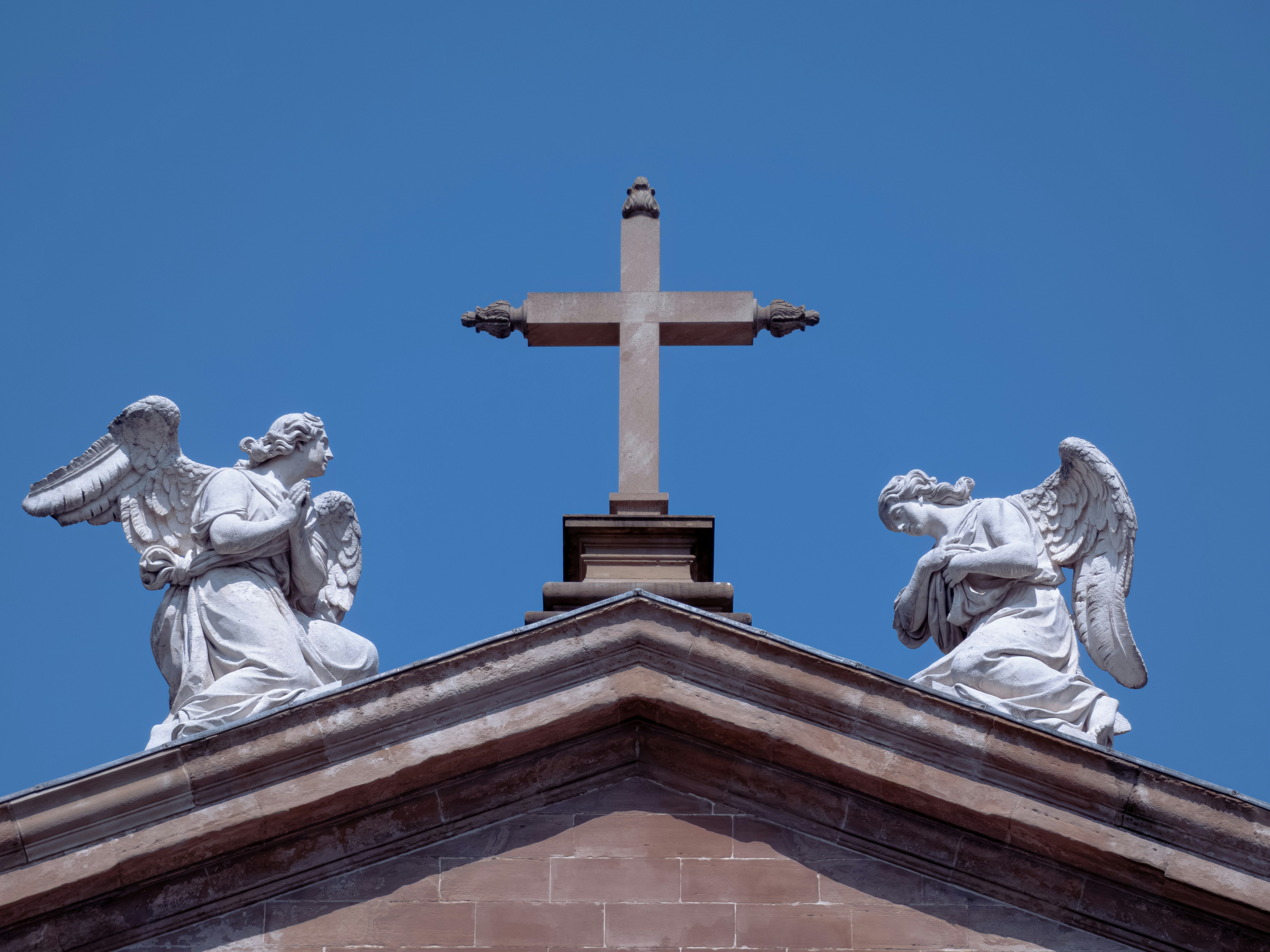Cross at the Peak: Angelic Sculptures Guard the Roofline