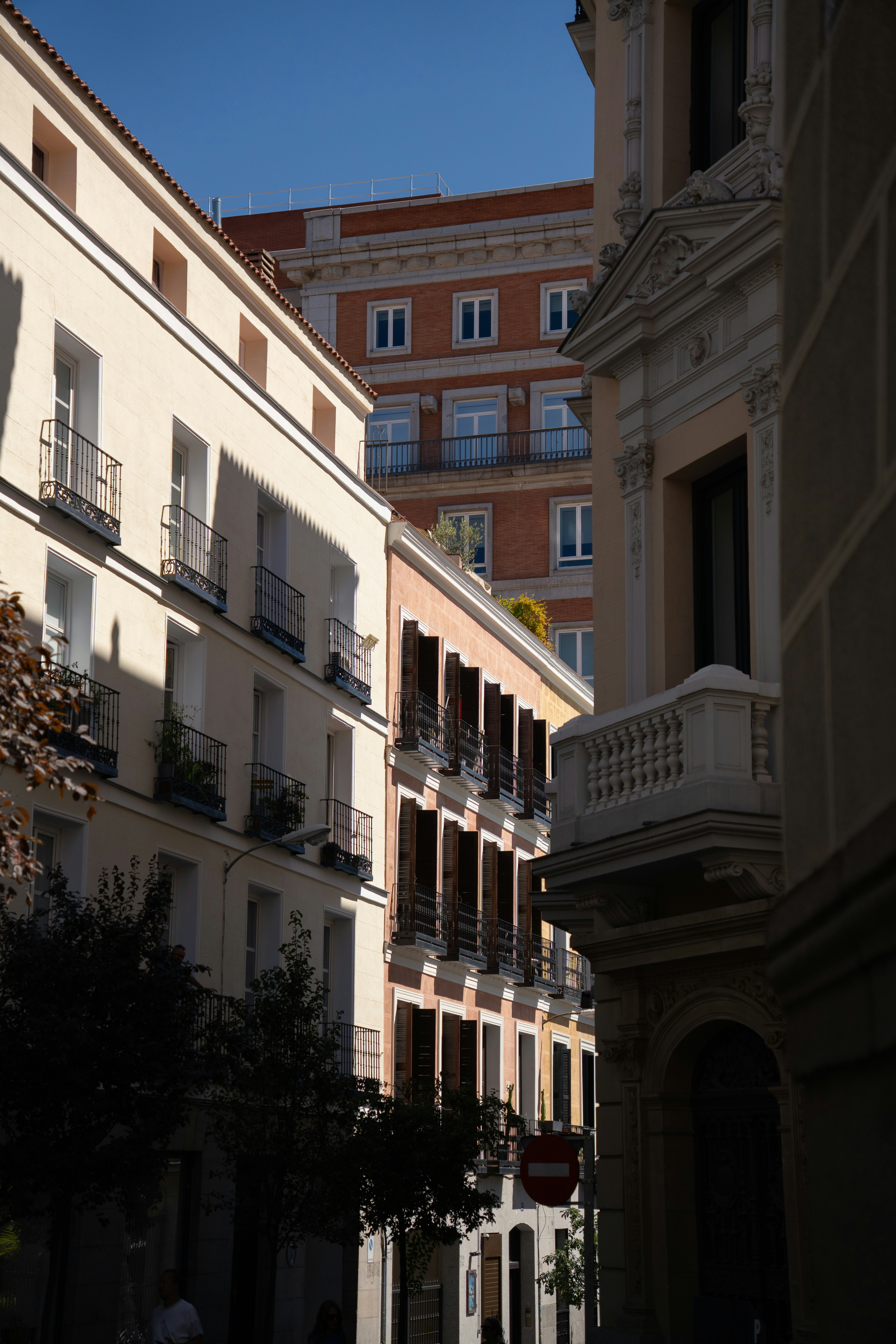 Sunlit Facades and Shadowed Alcoves in a Narrow Madrid-Style Street