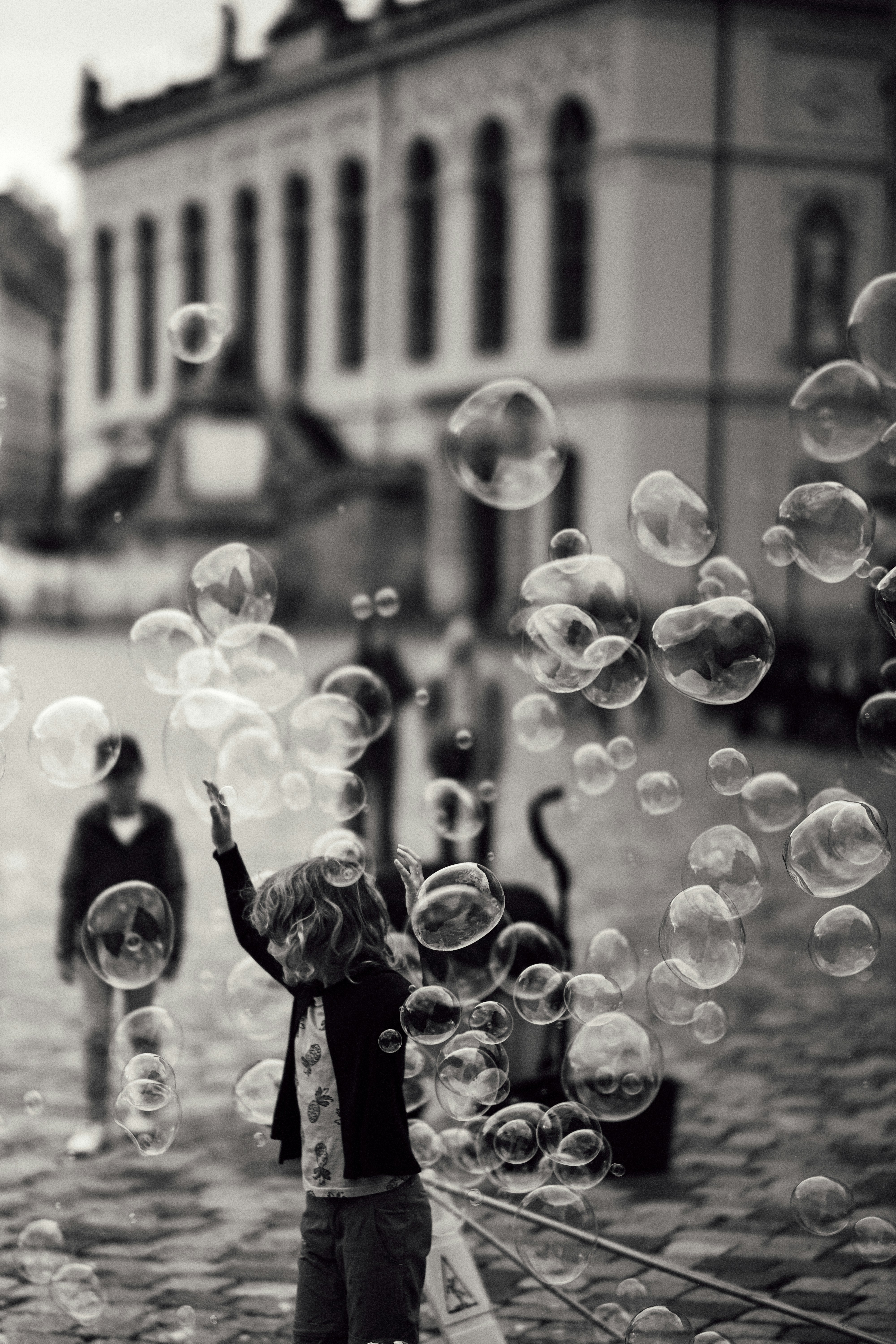 Bubbles in a City Play: Children Chase the Quiet Rain of Soap Orbs