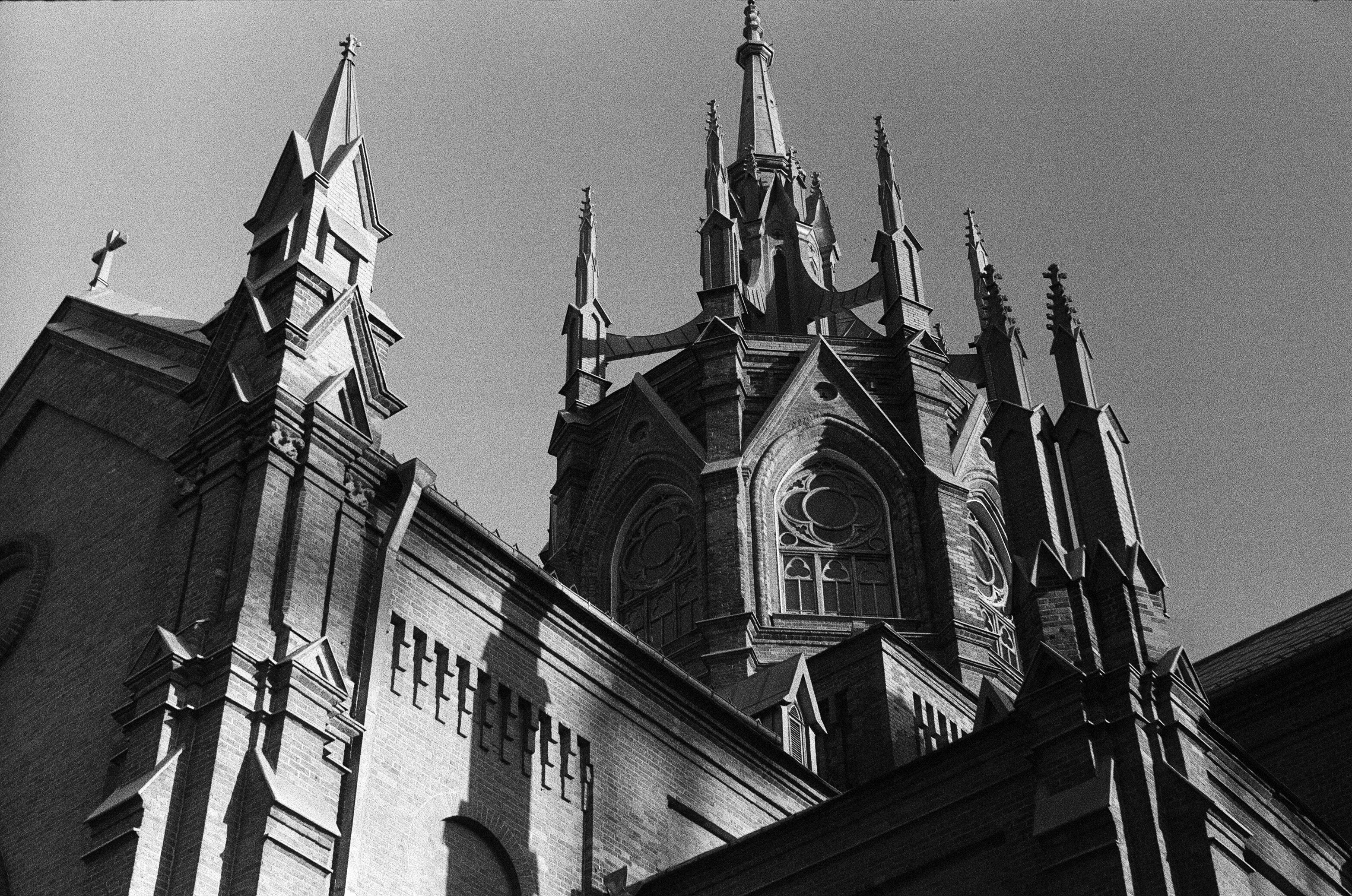Dark cathedral facade with towering spires and ornate windows, captured in black and white to emphasize architectural details.