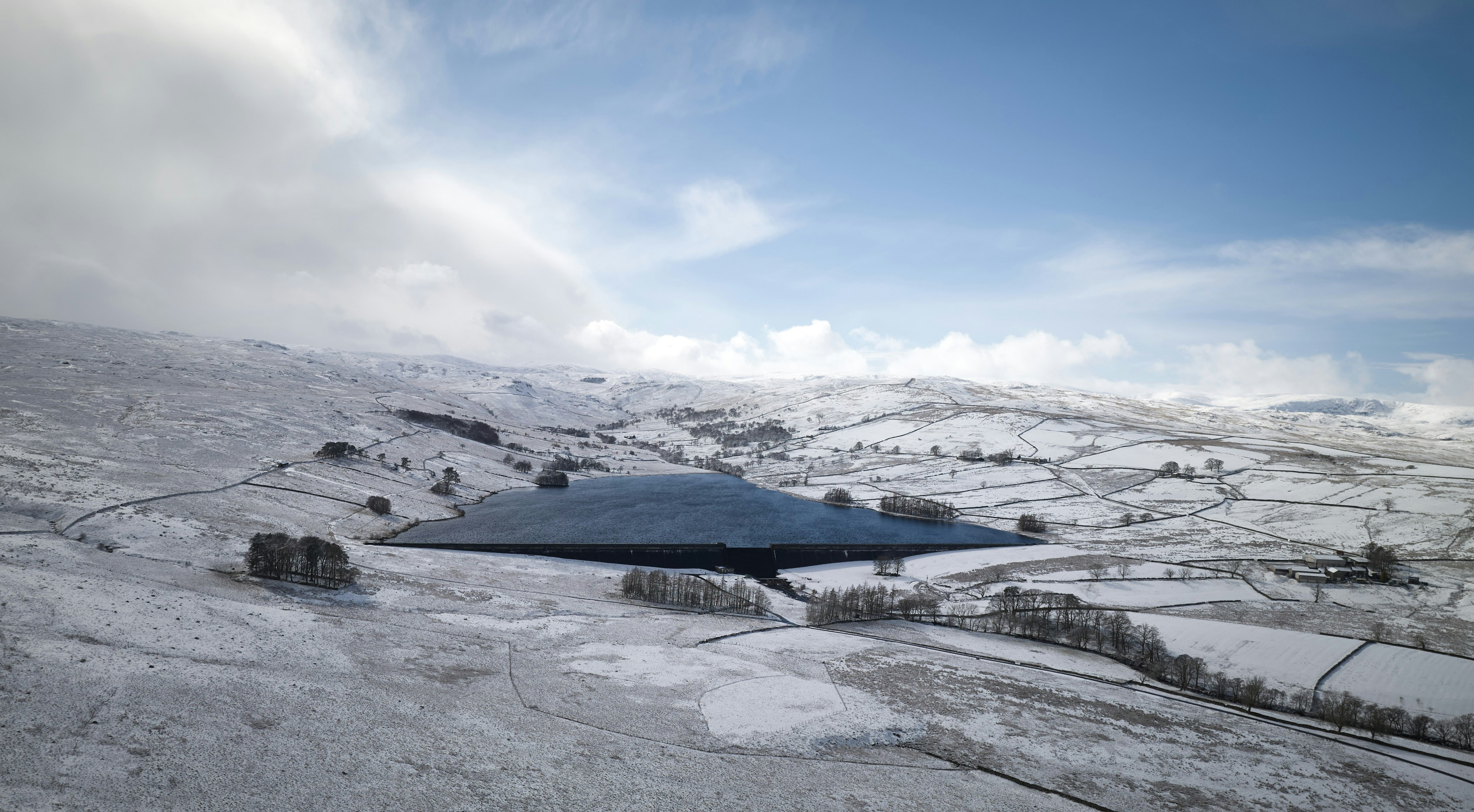 Snowfield Reservoir Under Wide Sky