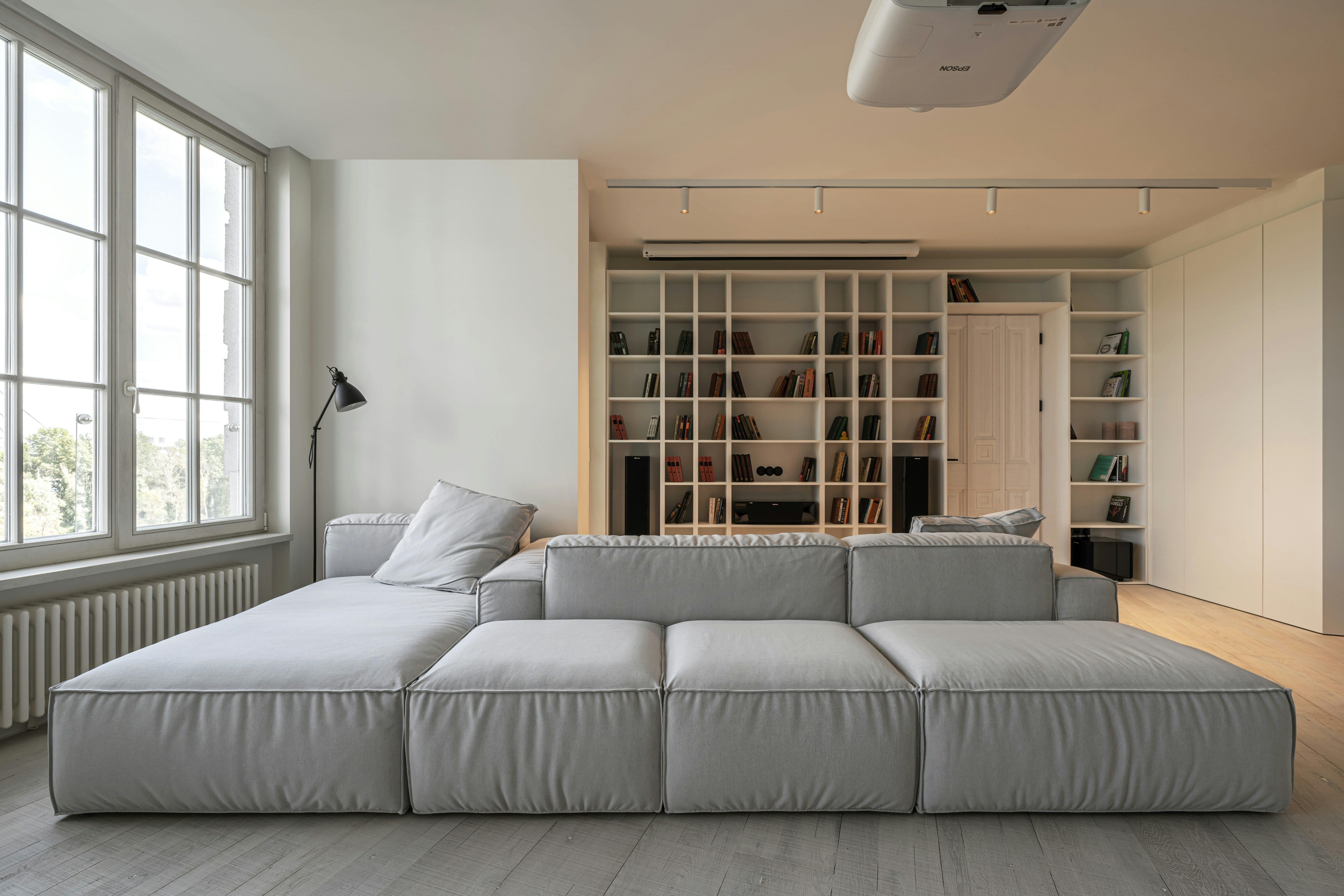 Minimalist Lounge: Soft Gray Modular Sofa Anchors a Sunlit Library Living Room