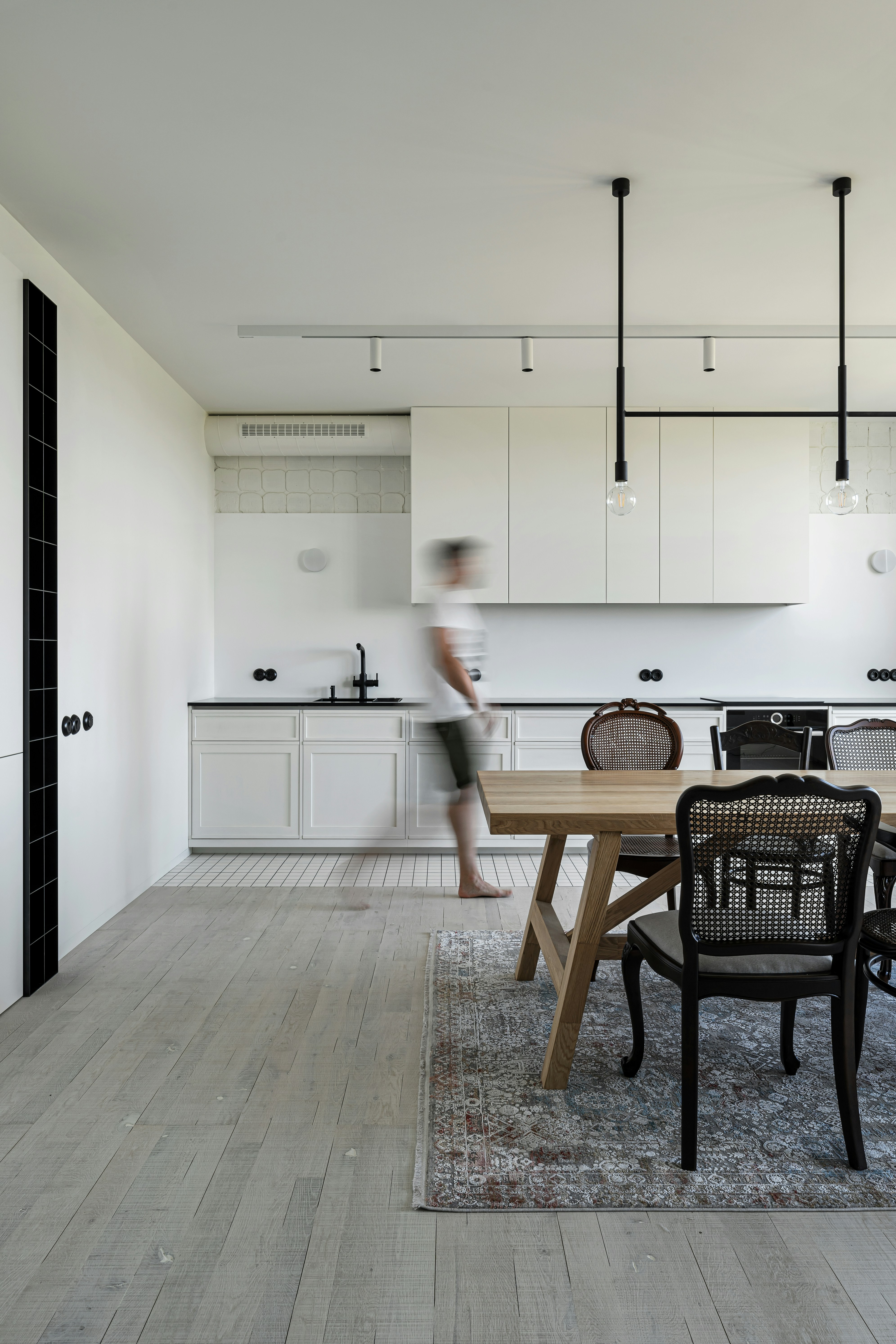 Minimalist Kitchen Drift: A Quiet Moment Across White Cabinets and Wooden Table