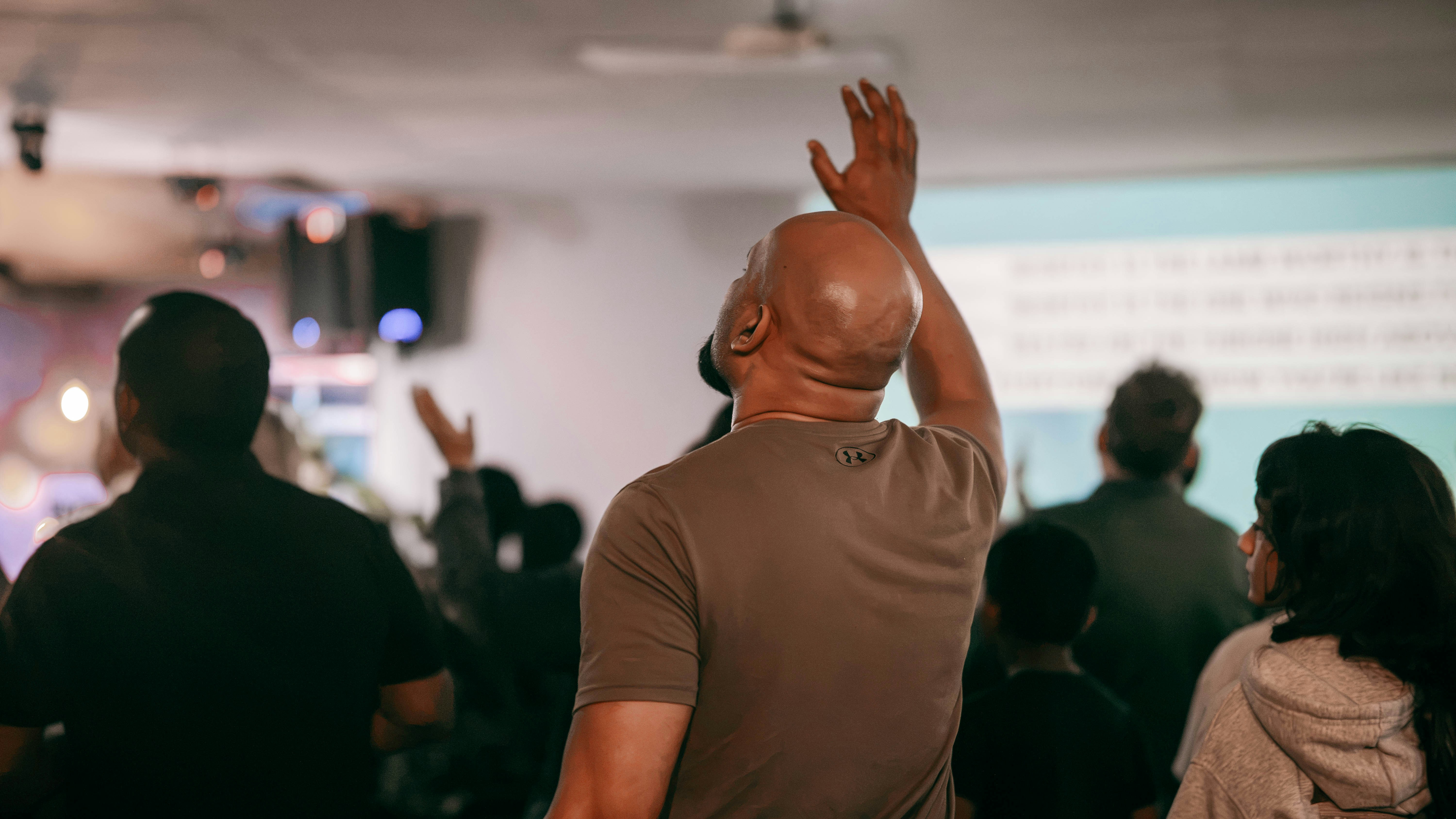Center Stage: A Raised Hand Reaches Toward the Lighted Crowd