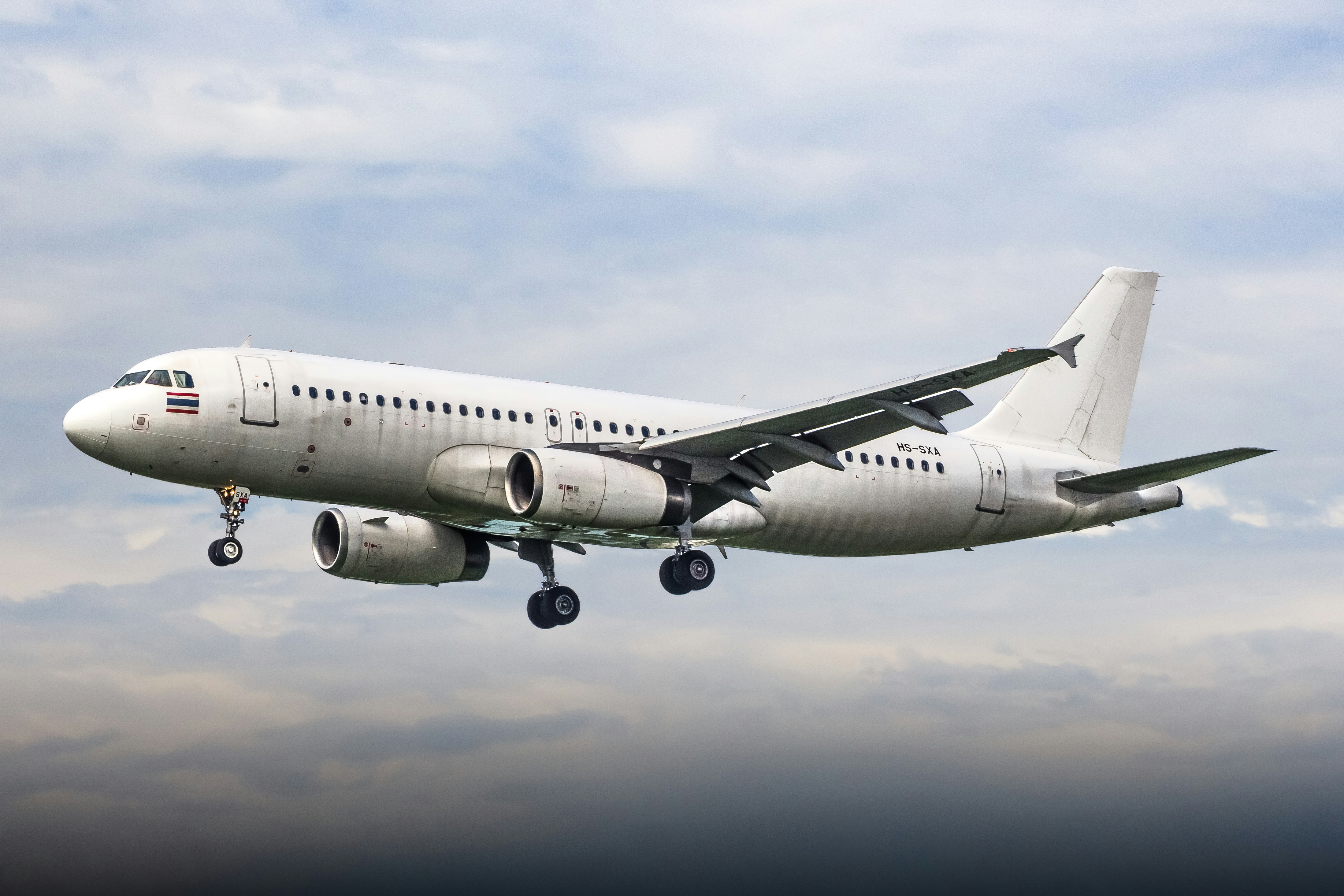Midflight silhouette: A white airliner glides above a clouded horizon