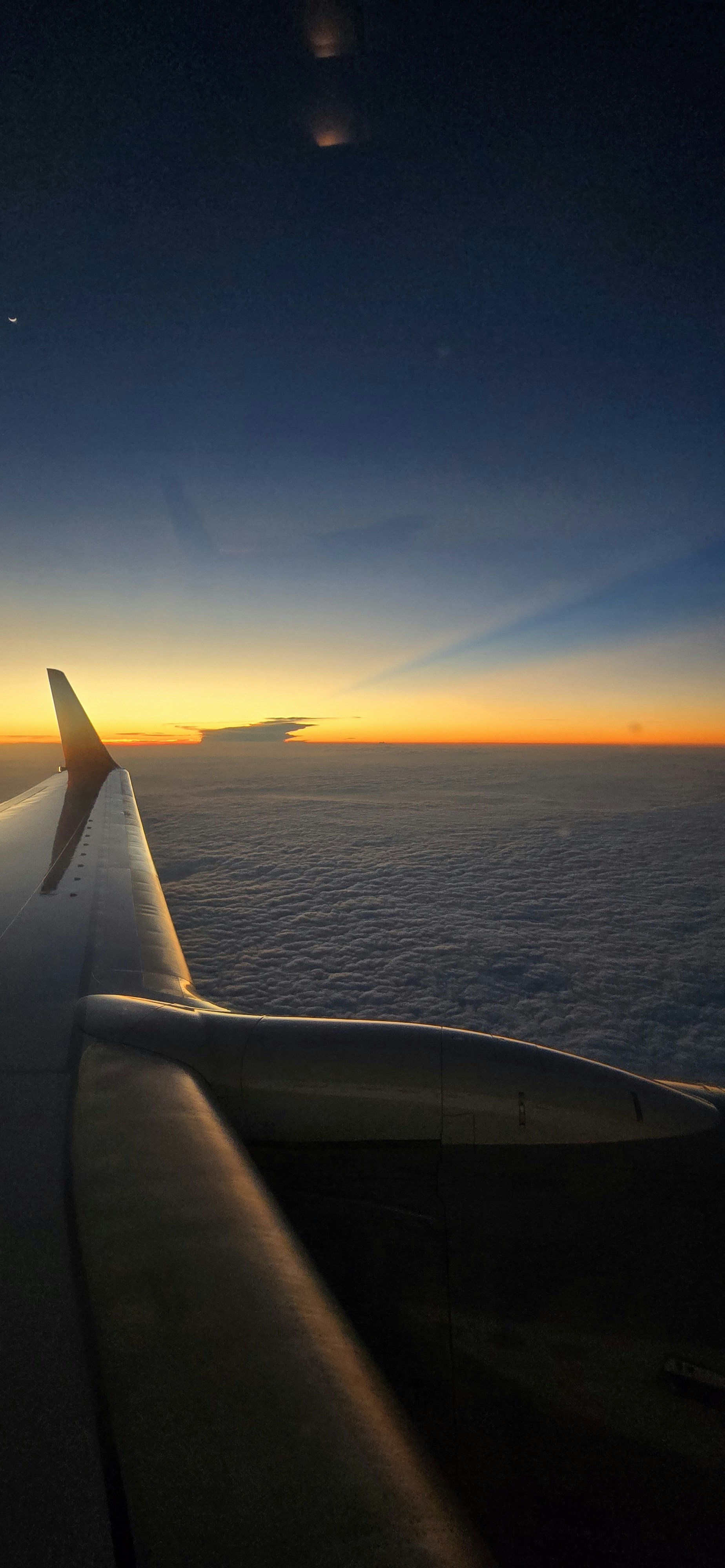 Sunset over the wing: a narrow horizon of light from the window