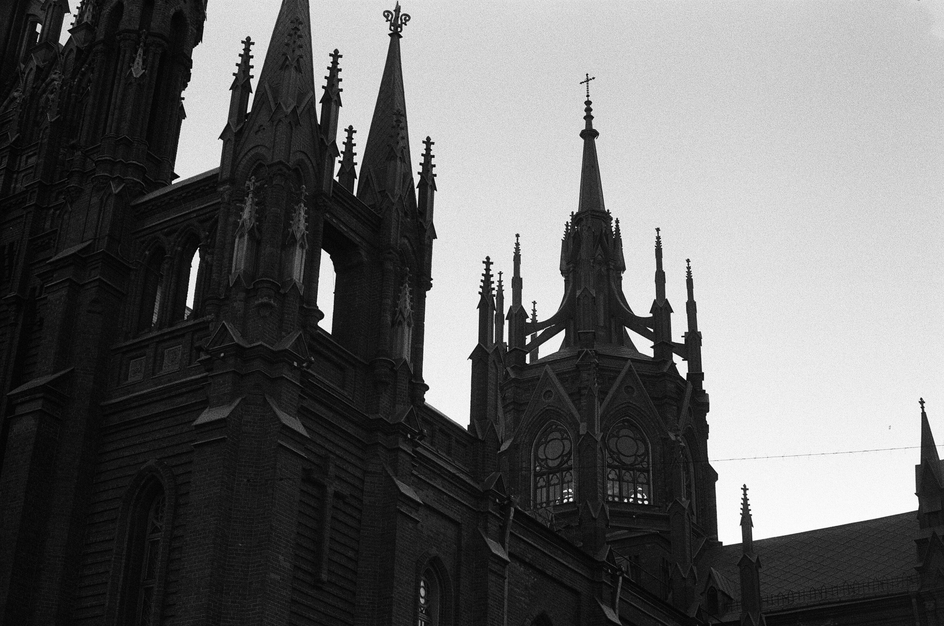 Dark stone spires rise over intricate arches in a European cathedral, captured in grayscale to emphasize architecture and contrast.