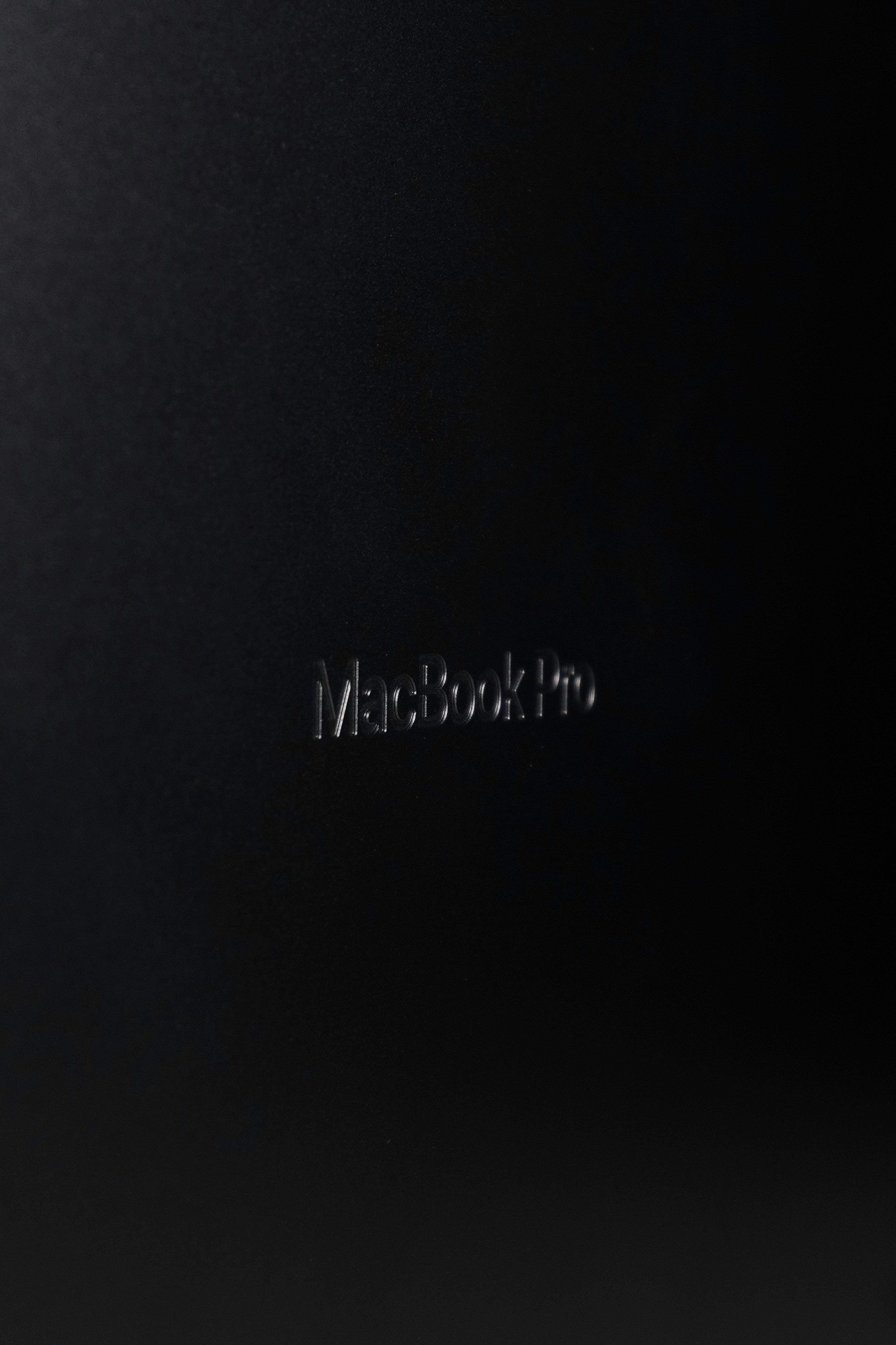 Dark Branding in Shadow: MacBook Pro Text Emerges from the Void