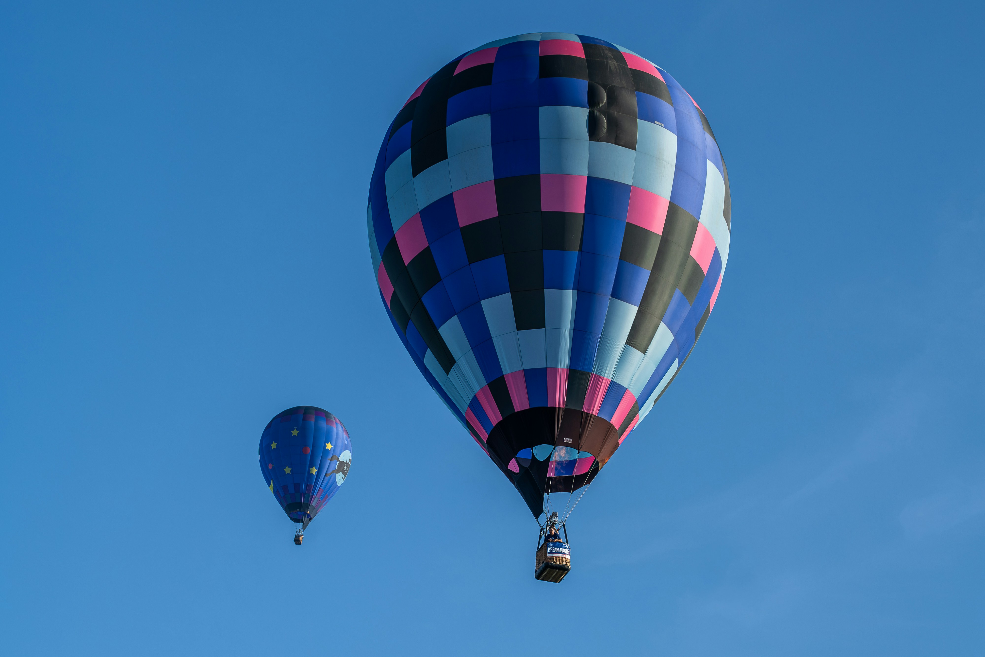 Colorful Giant and Distant Mini: Balloons Ascend Under Clear Skies
