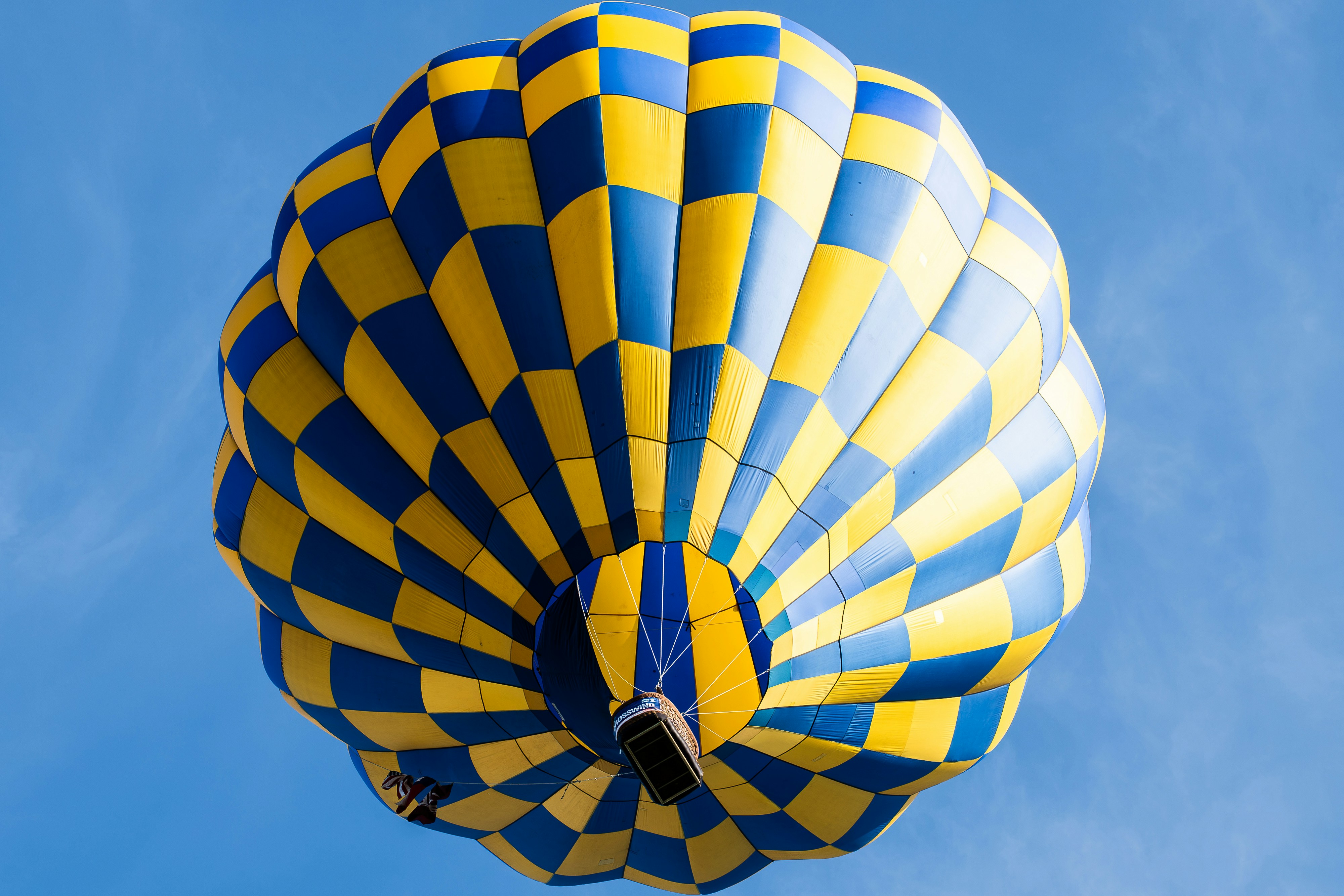 Yellow-Blue Spiral: A Balloon's Ascent Against a Clear Sky