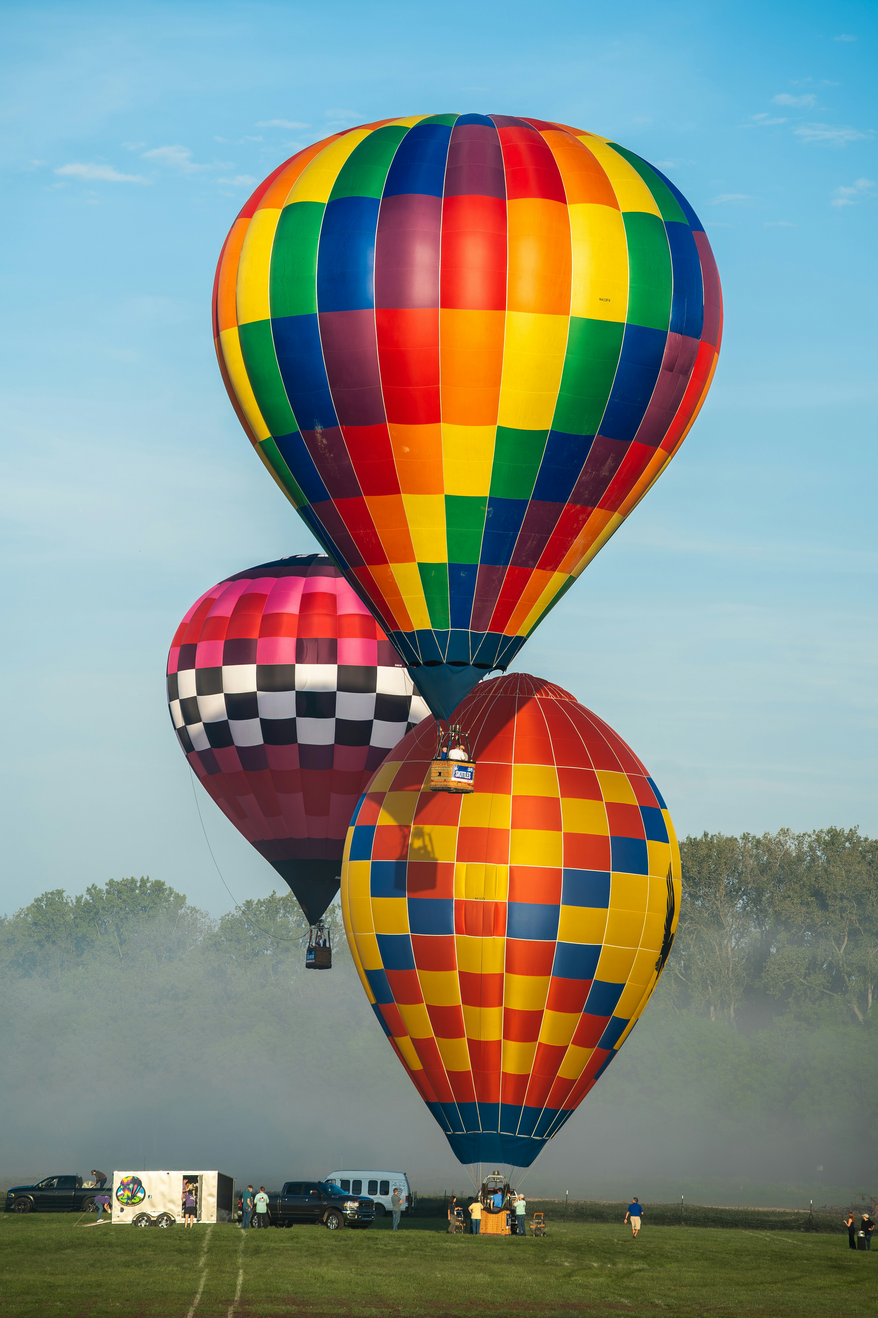 Colorful Ascension: A Fleet of Balloons Lifts Over a Misty Field