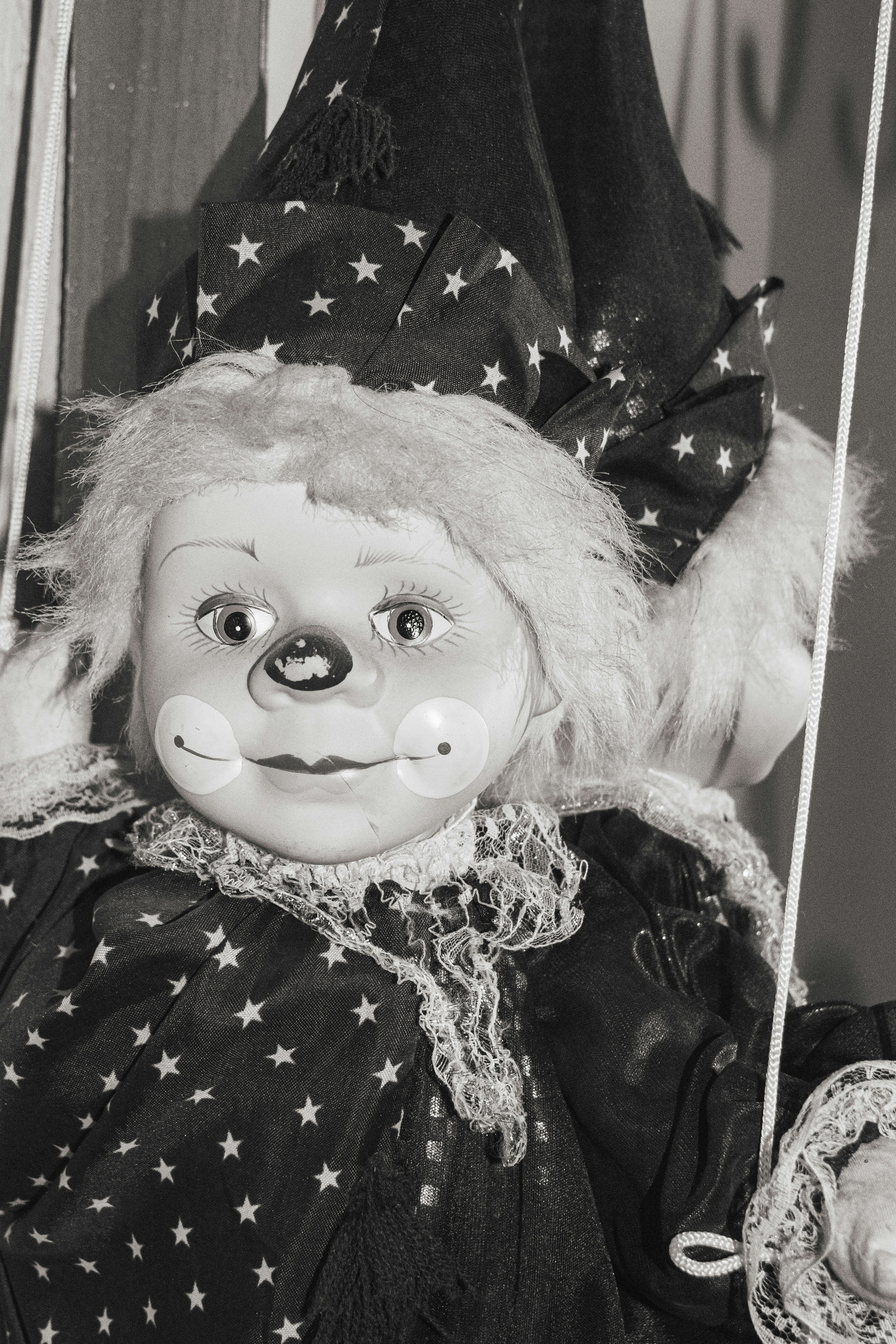 Starry Conjuror: A Vintage Clown Doll Under a Dim Spotlight