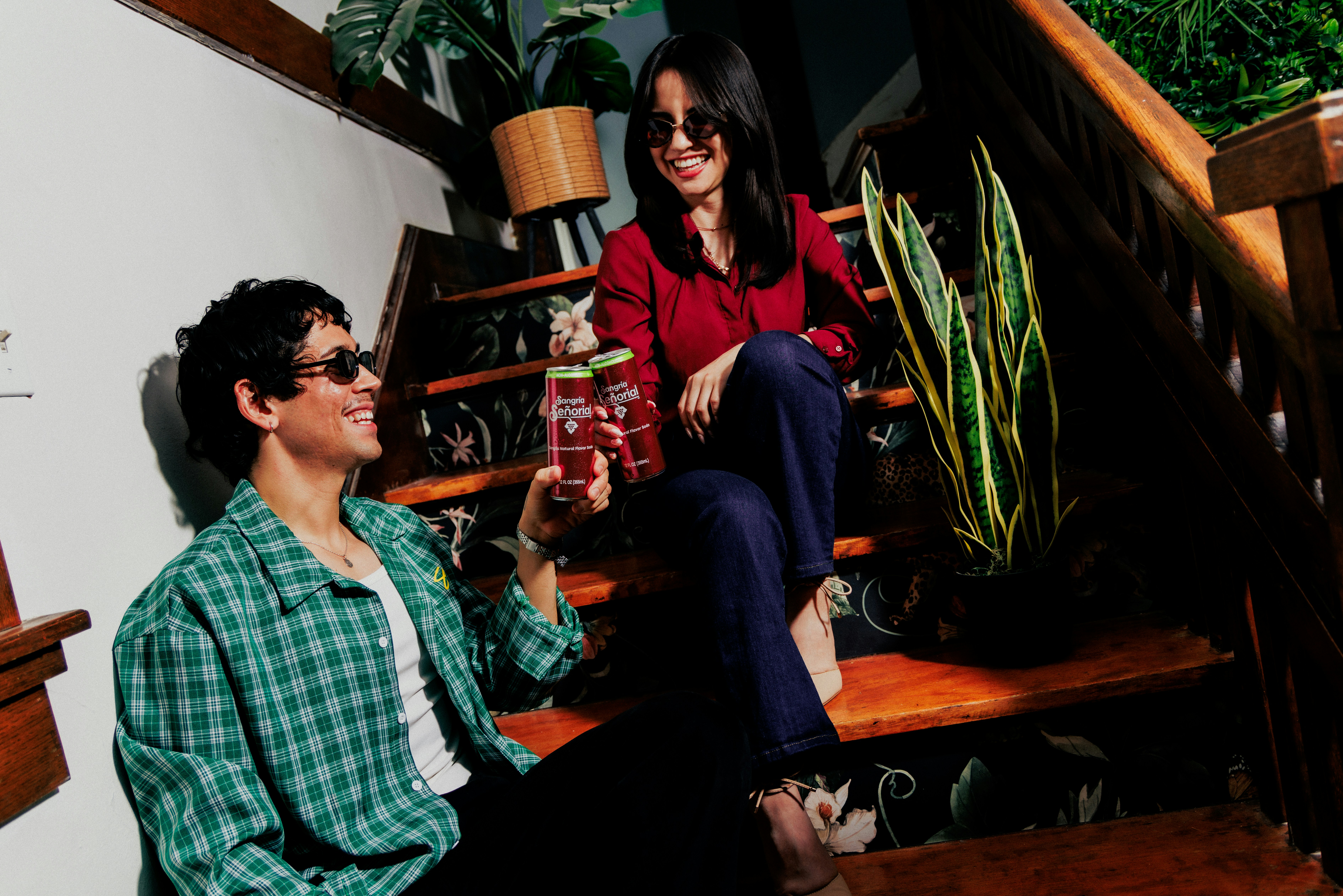 Conversations on a Sunlit Stair: Friends Share a Drink on a Lush Indoor Stairway